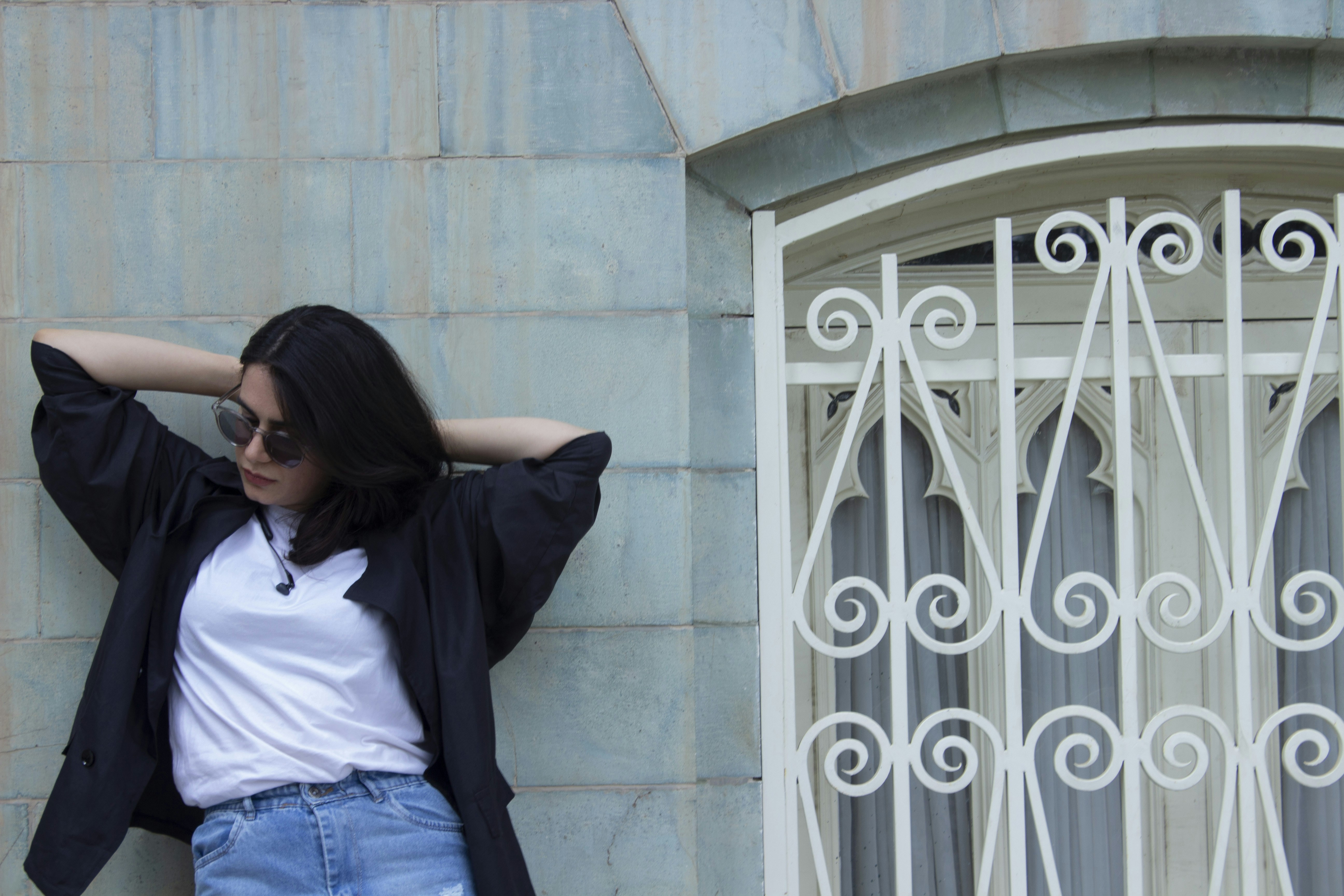 A woman leaning against a wall with her arms behind her head photo – Free Model Image on Unsplash
