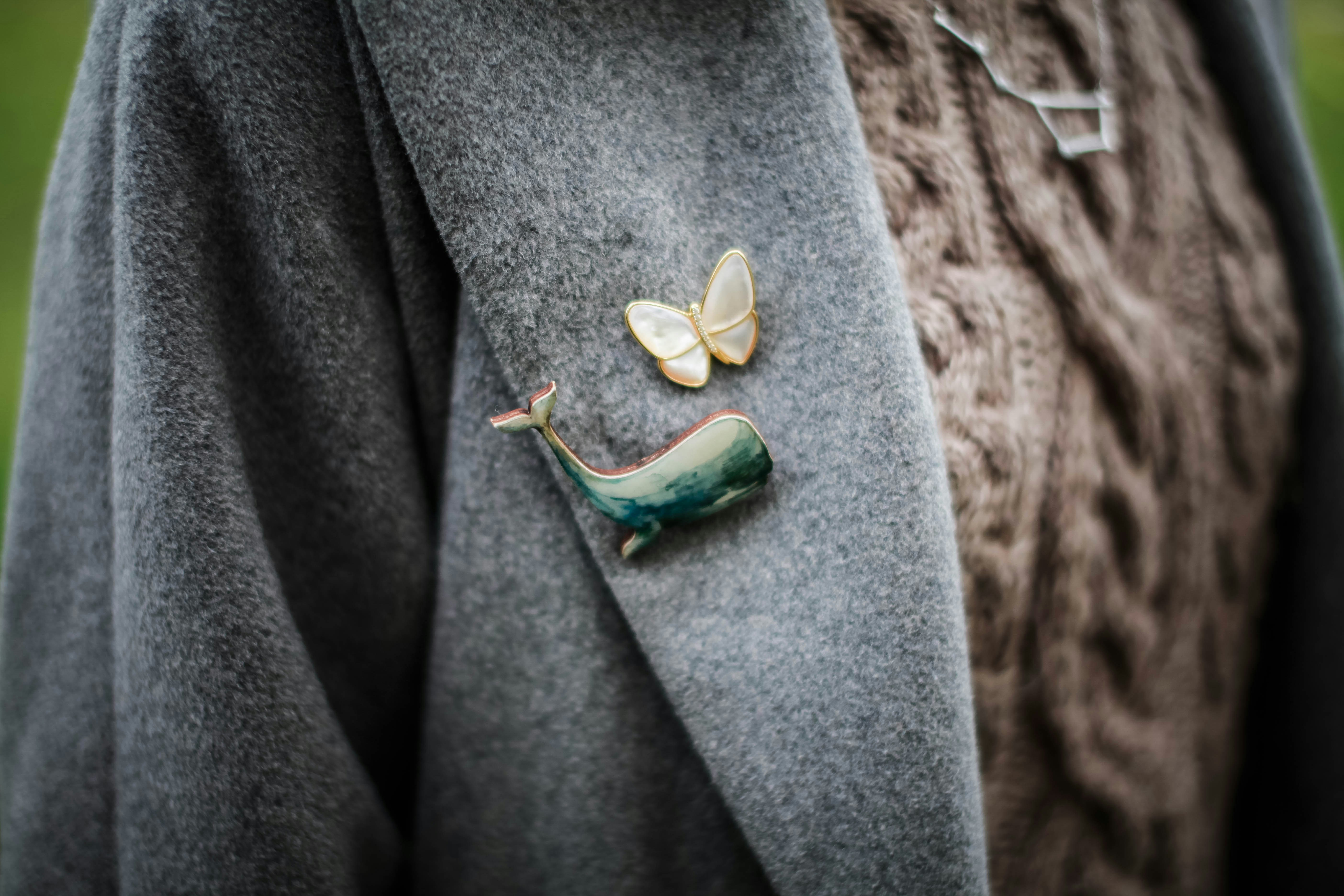 a close up of a person wearing a jacket with a butterfly pin on it