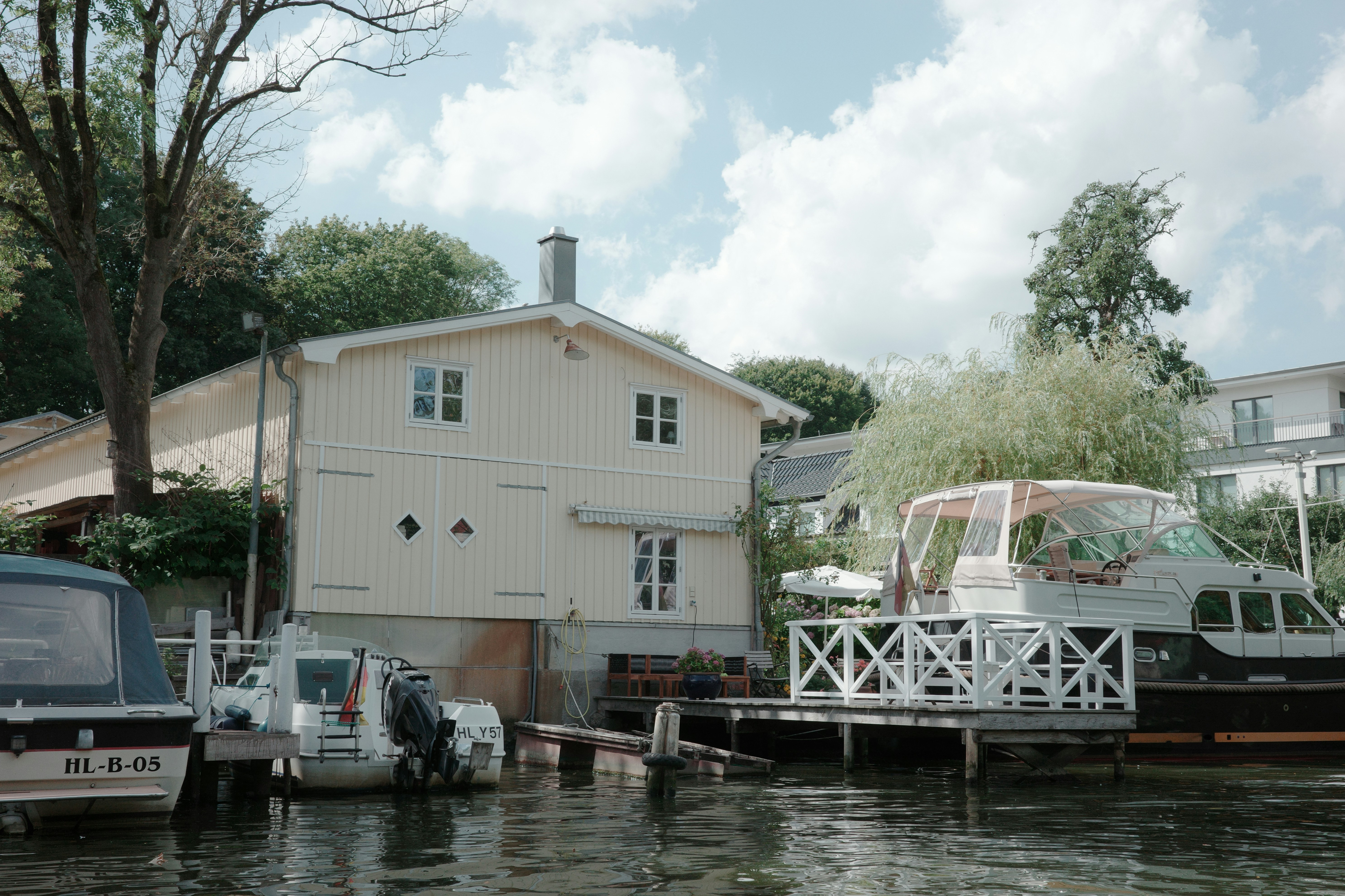 Yellow boathouse with moored boats under a partly cloudy sky in Lübeck, Germany.
