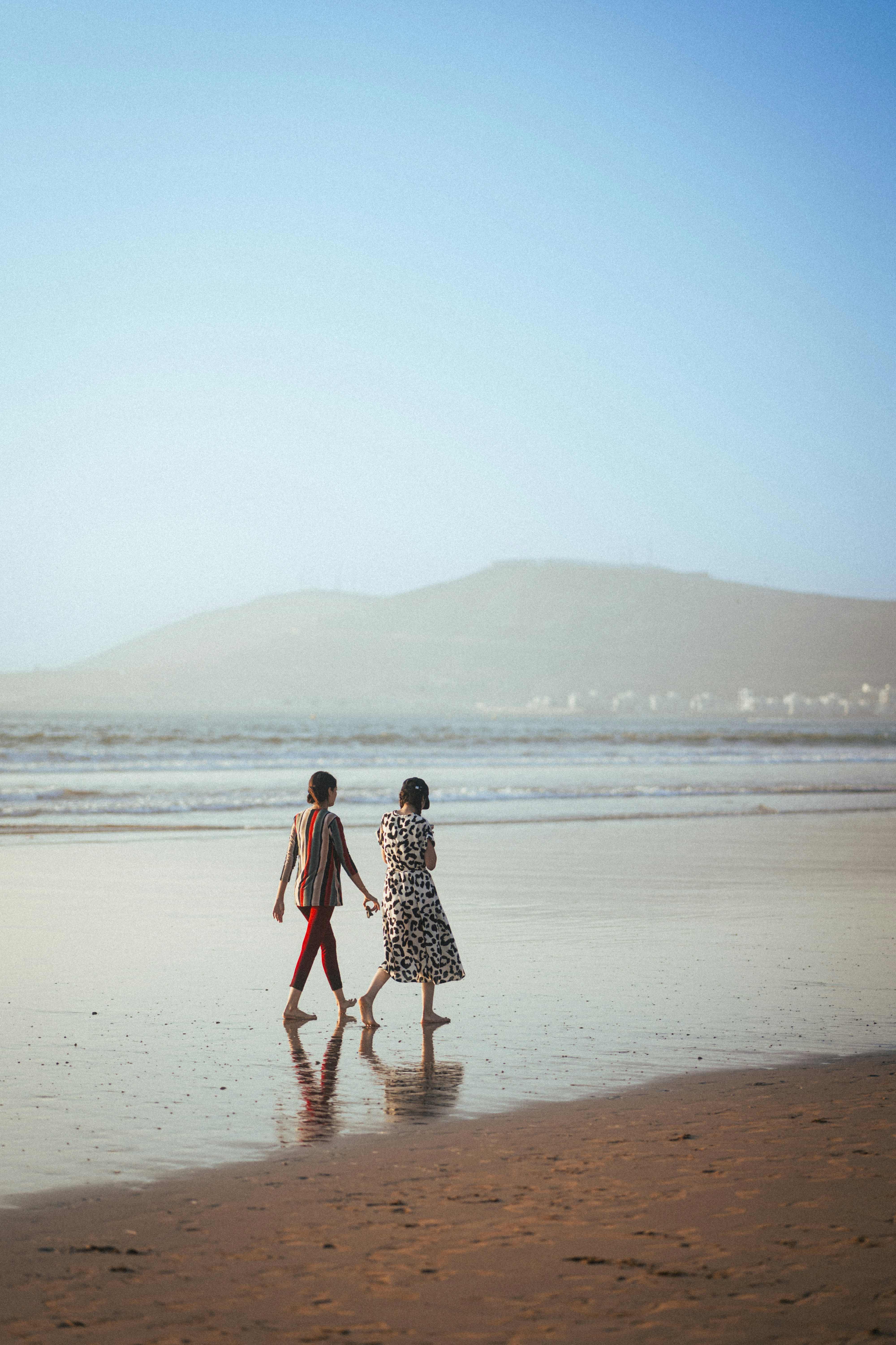 Deux personnes marchant sur une plage en se tenant la main photo ...