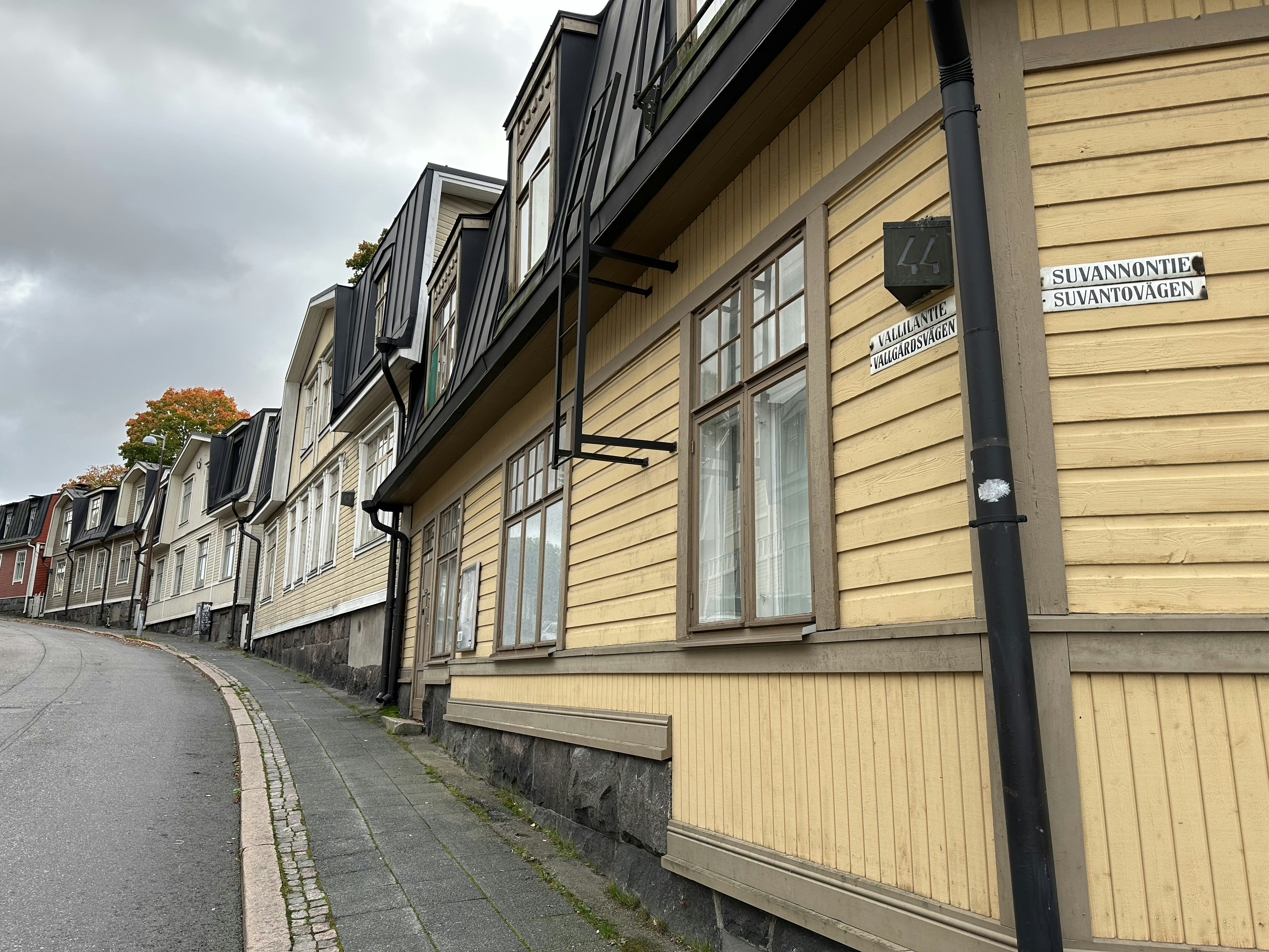 Wooden house district in Vallila, Helsinki Finland. | a row of houses with a street sign in front of them