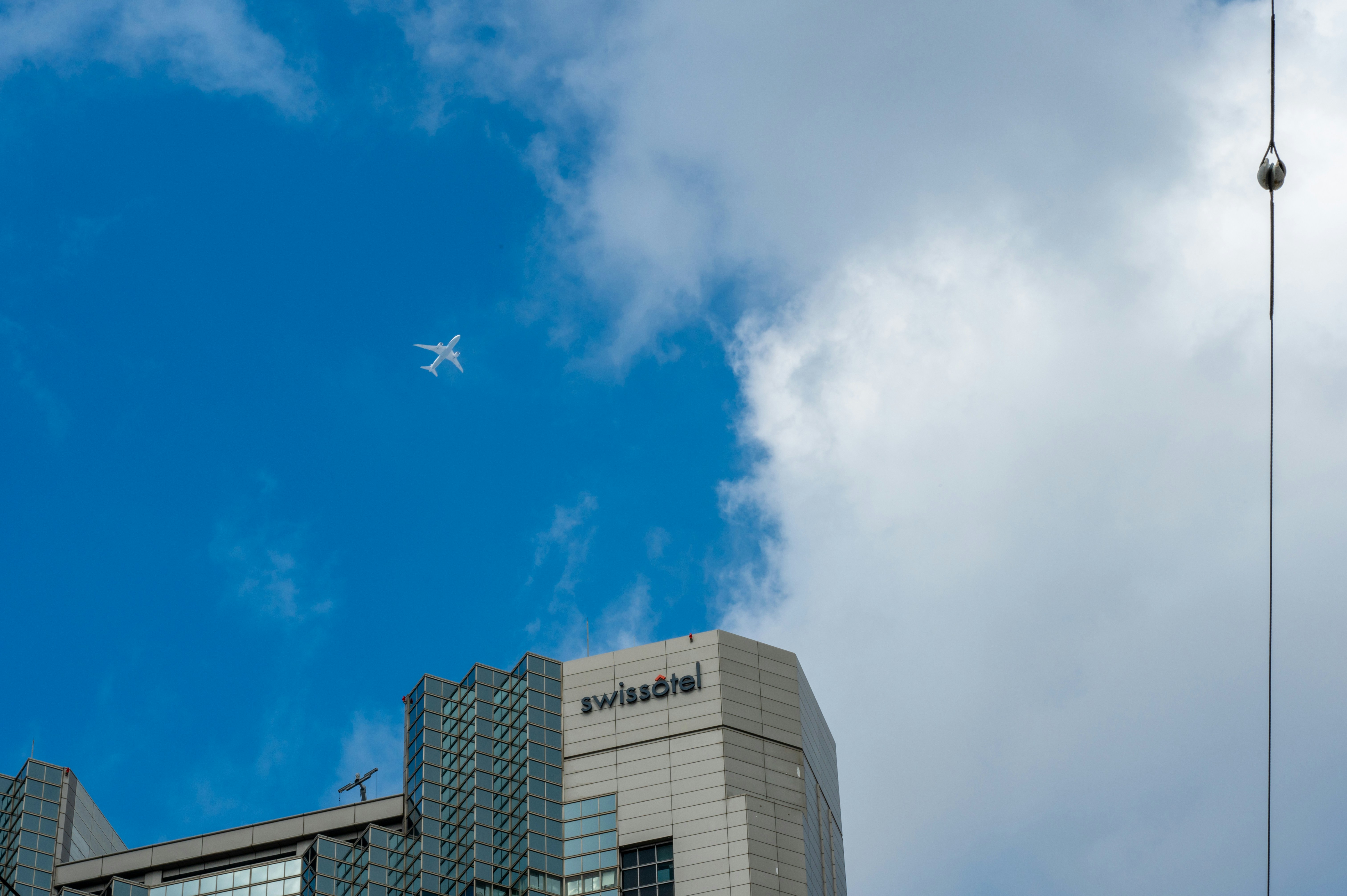 Swissotel Azure: City Tower Under a Vast Sky with a Drifting Jet