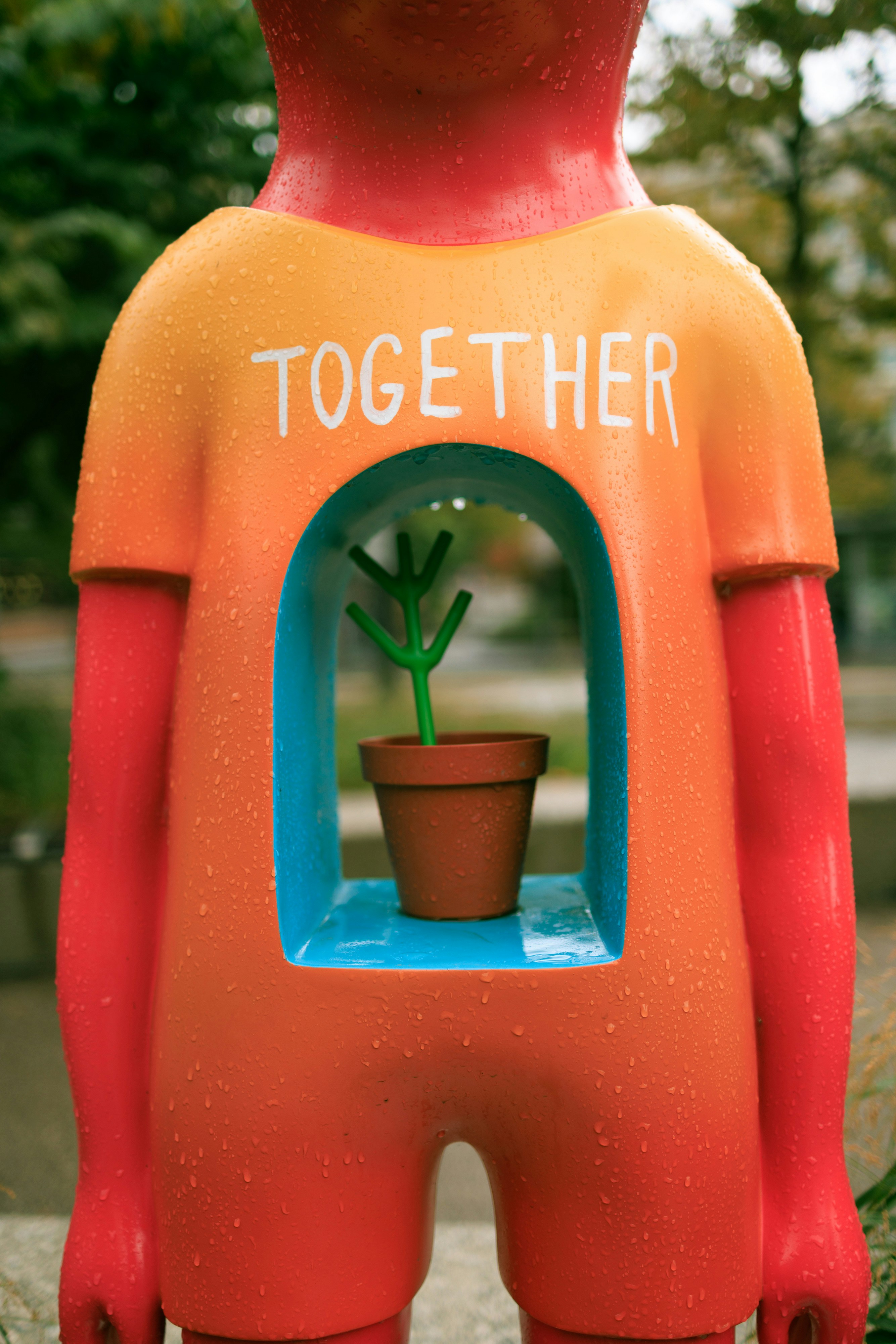 A sculpture, with the words "together" painted across the chest, sits in a downtown public park.