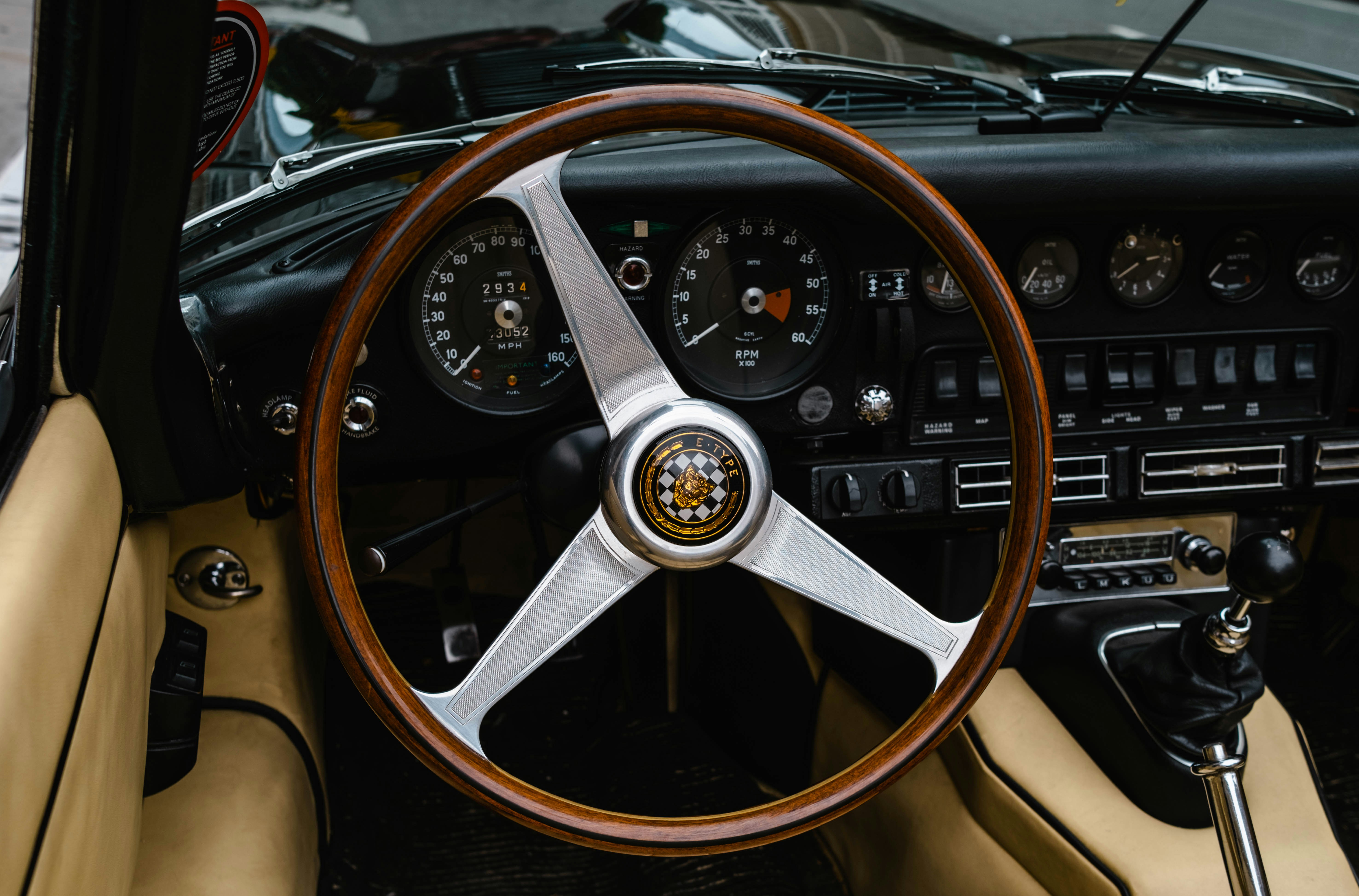 Classic car interior with a wooden steering wheel and vintage dashboard gauges.