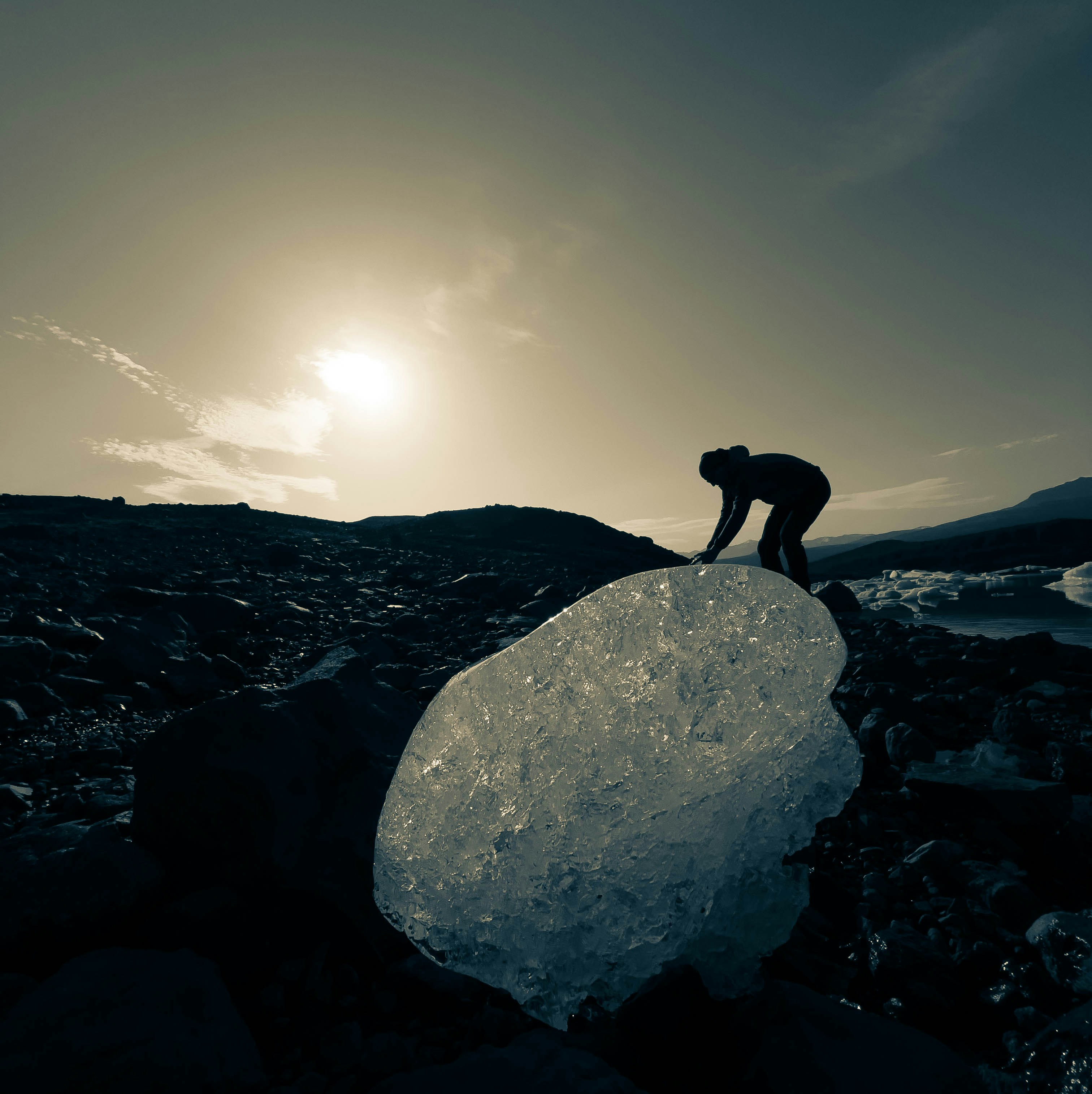 Icebound Ascent: A Silhouetted Figure on a Glacial Pebble