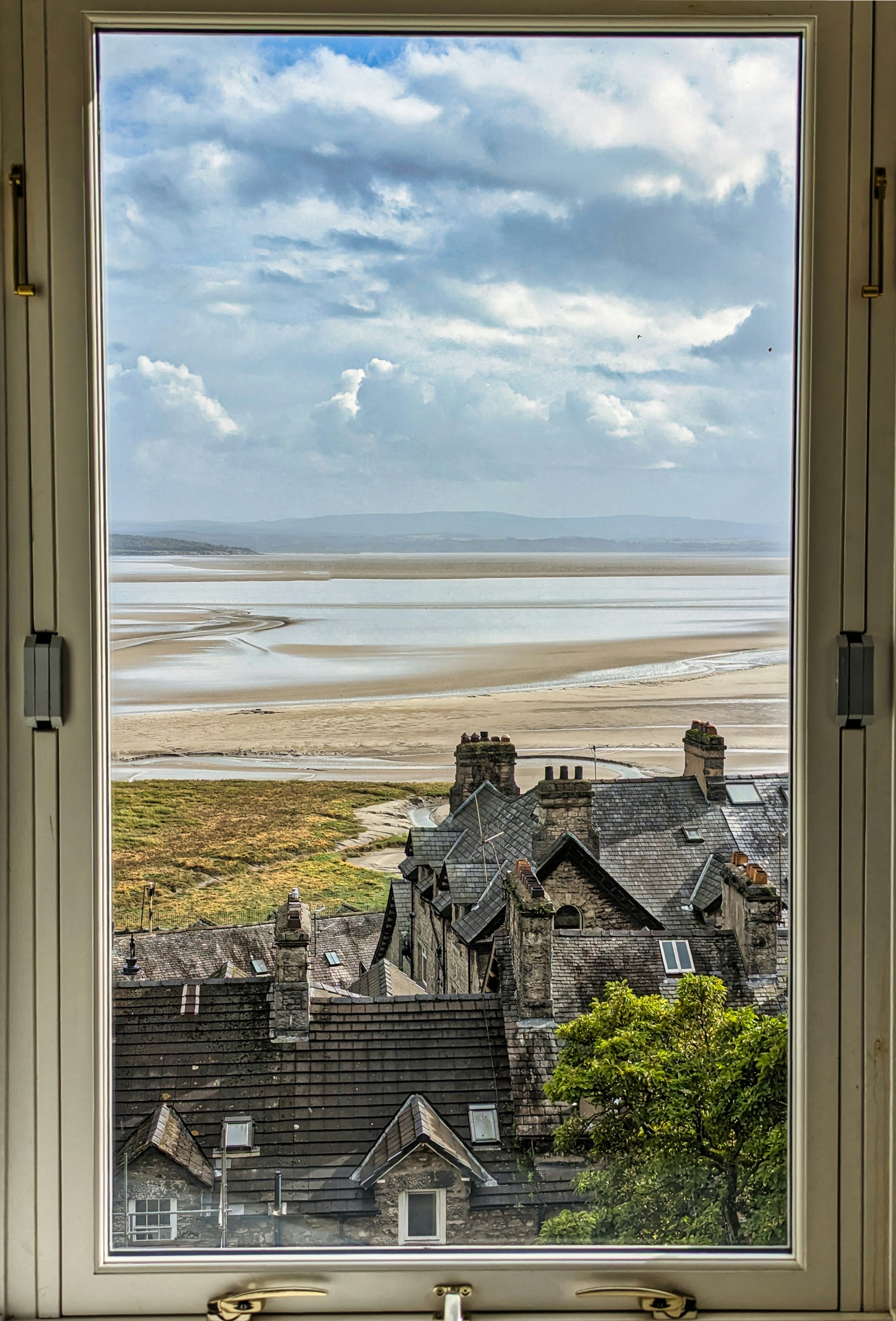 Coastal Village Window: Ridge of Slate Roofs Framing a Tidal Landscape