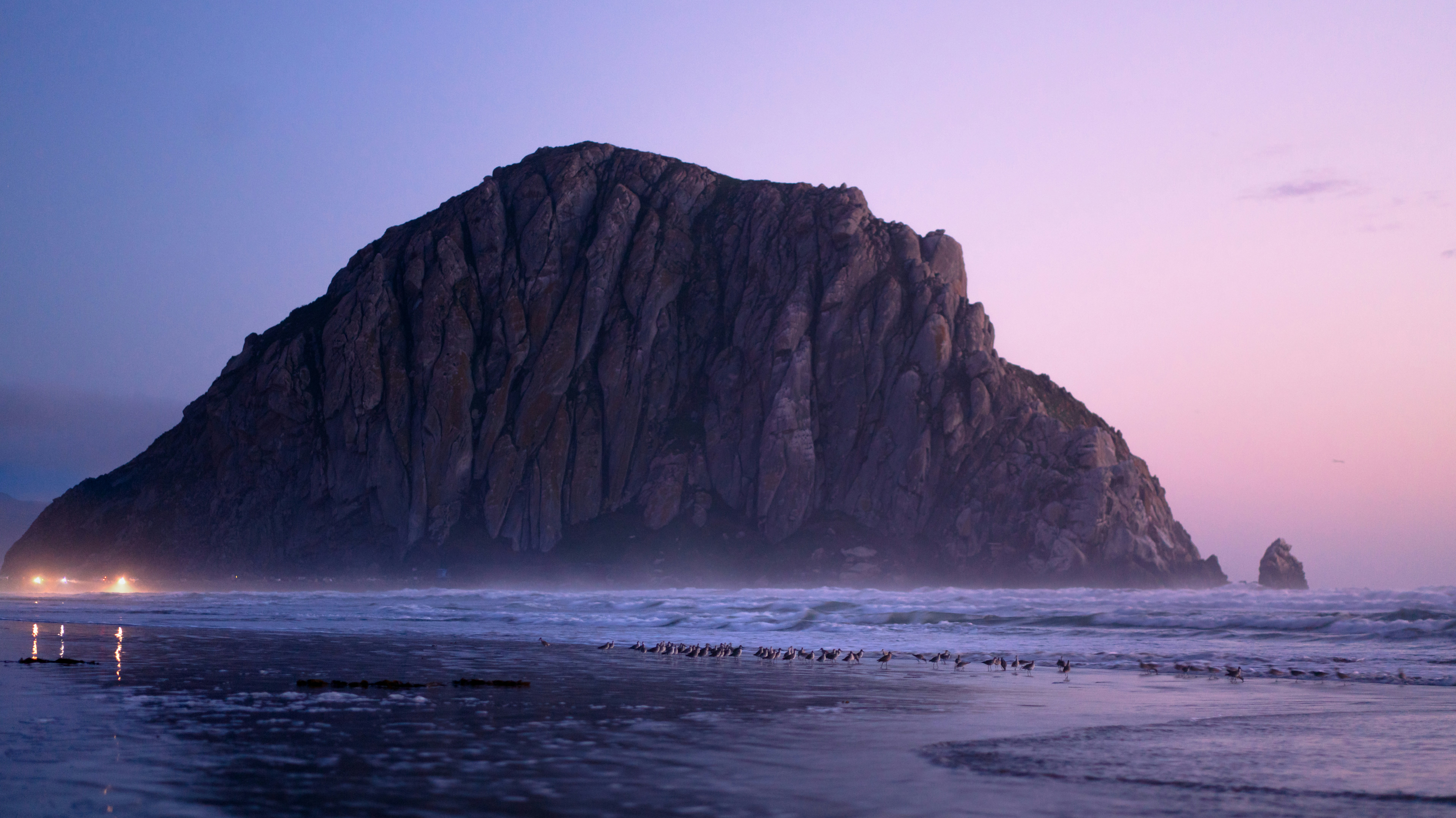 A large rock sticking out of the ocean next to a beach photo – Free ...