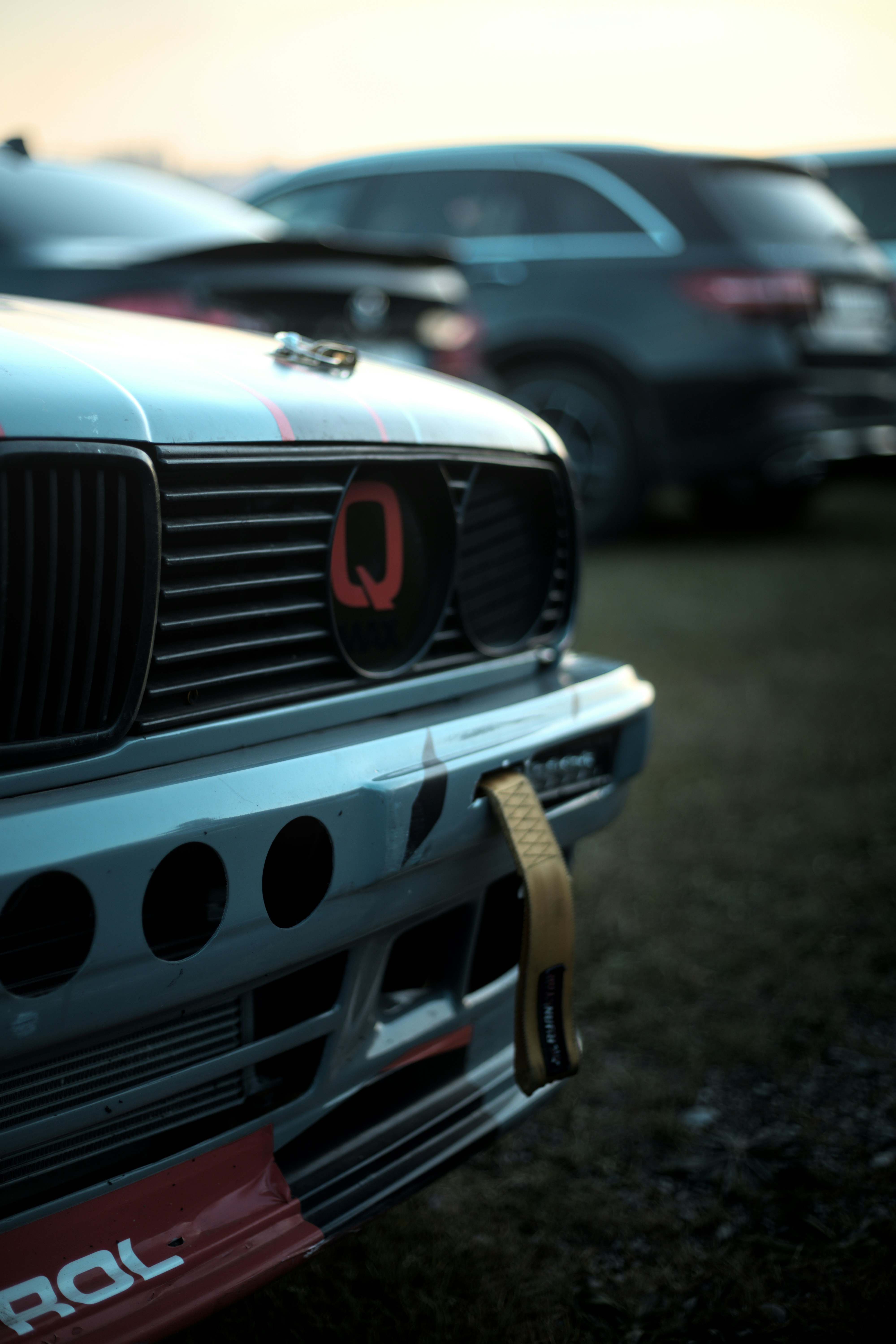 Close-up of a race car badge: bold grille with a stylized 'Q' emblem
