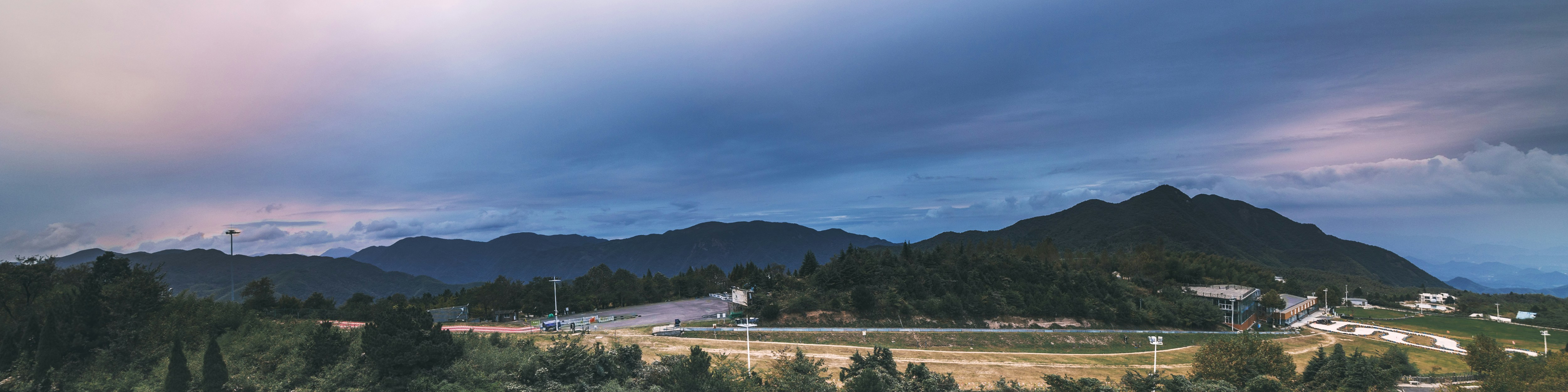 Twilight sky casts vibrant hues over a mountain landscape and raceway.