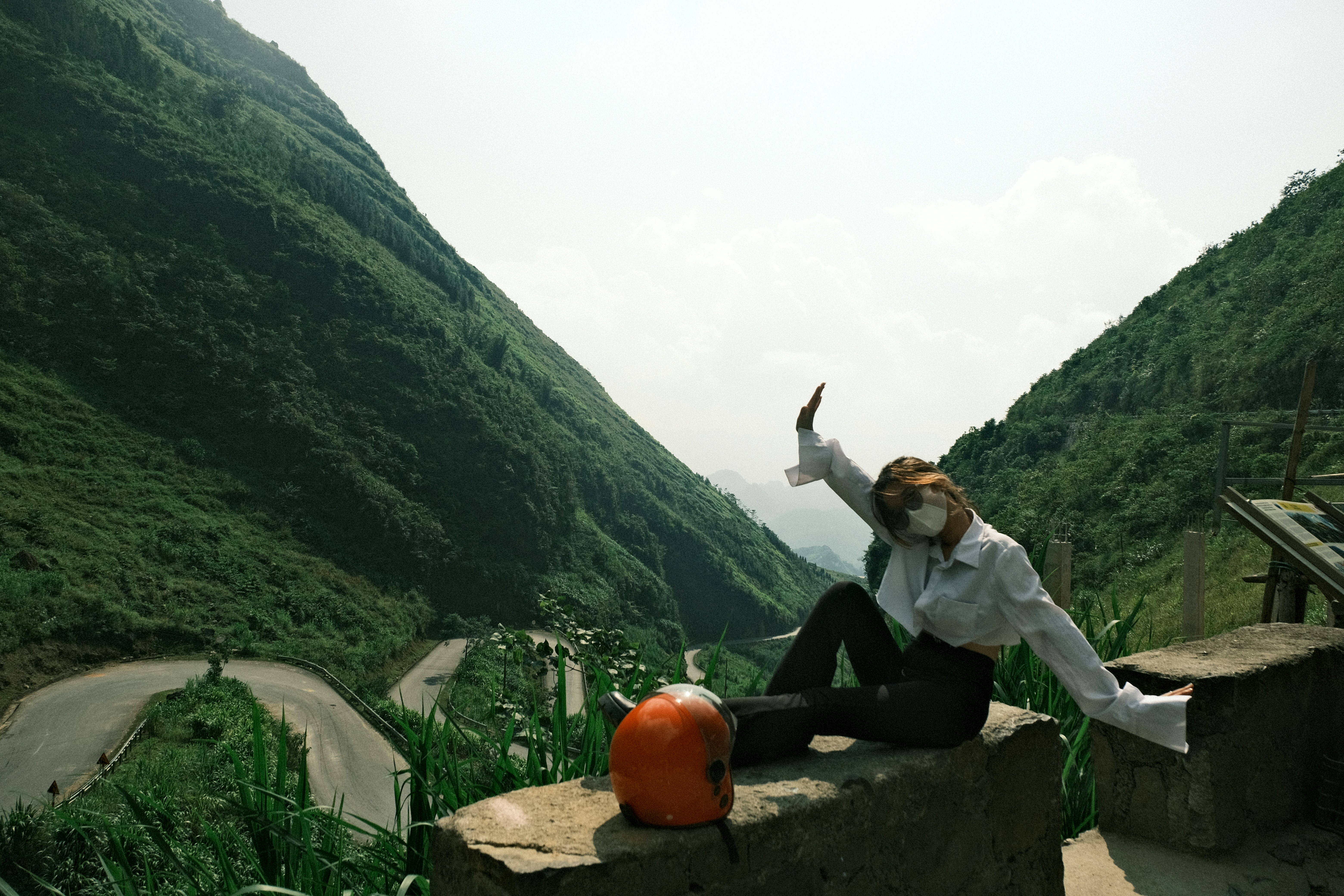A woman is sitting on a rock pointing at the sky photo – Free Face ...