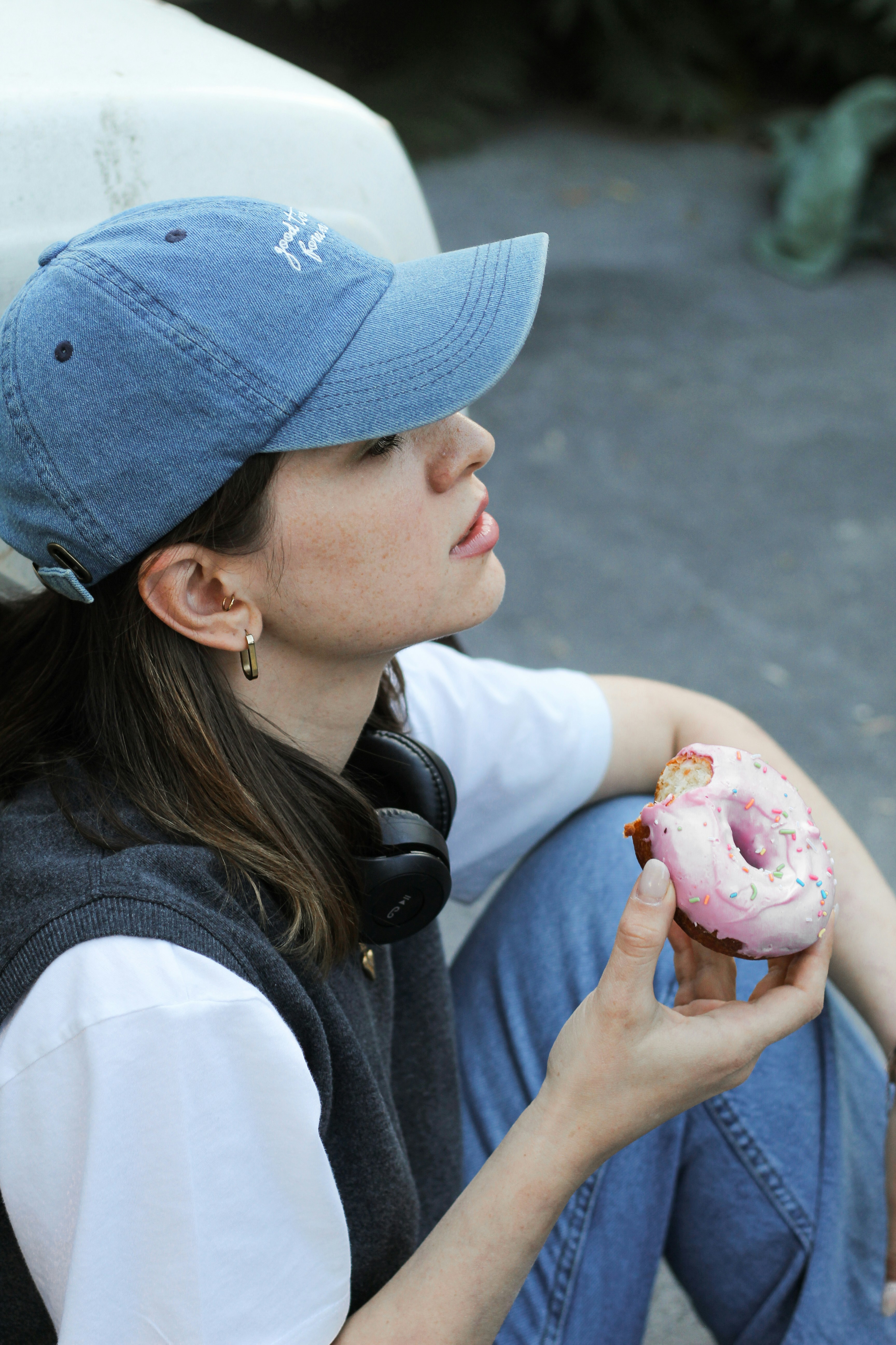 A woman sitting on the ground eating a doughnut photo – Free Food Image ...