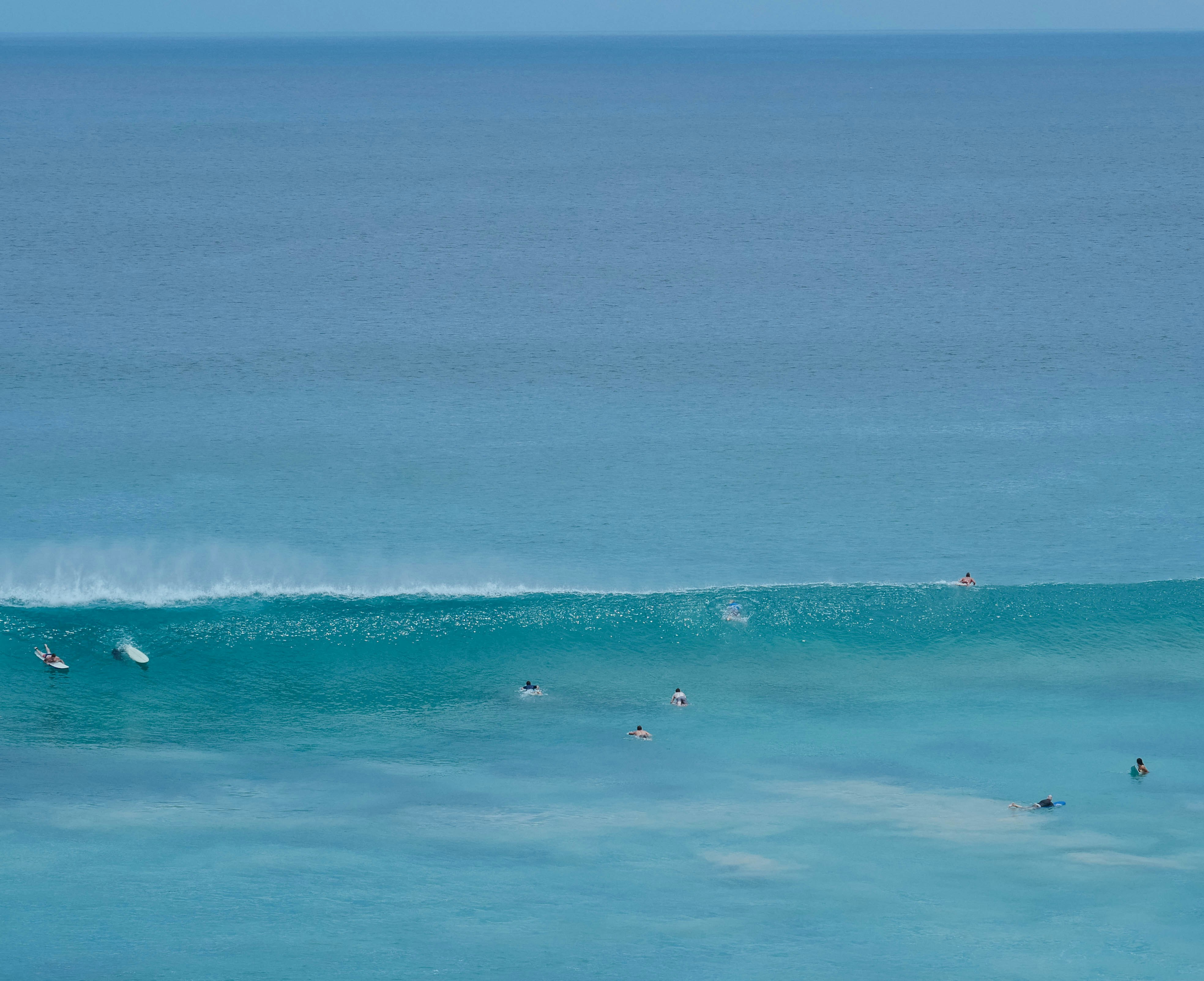 Turquoise Crest: Surfers Navigate a Long Ocean Break