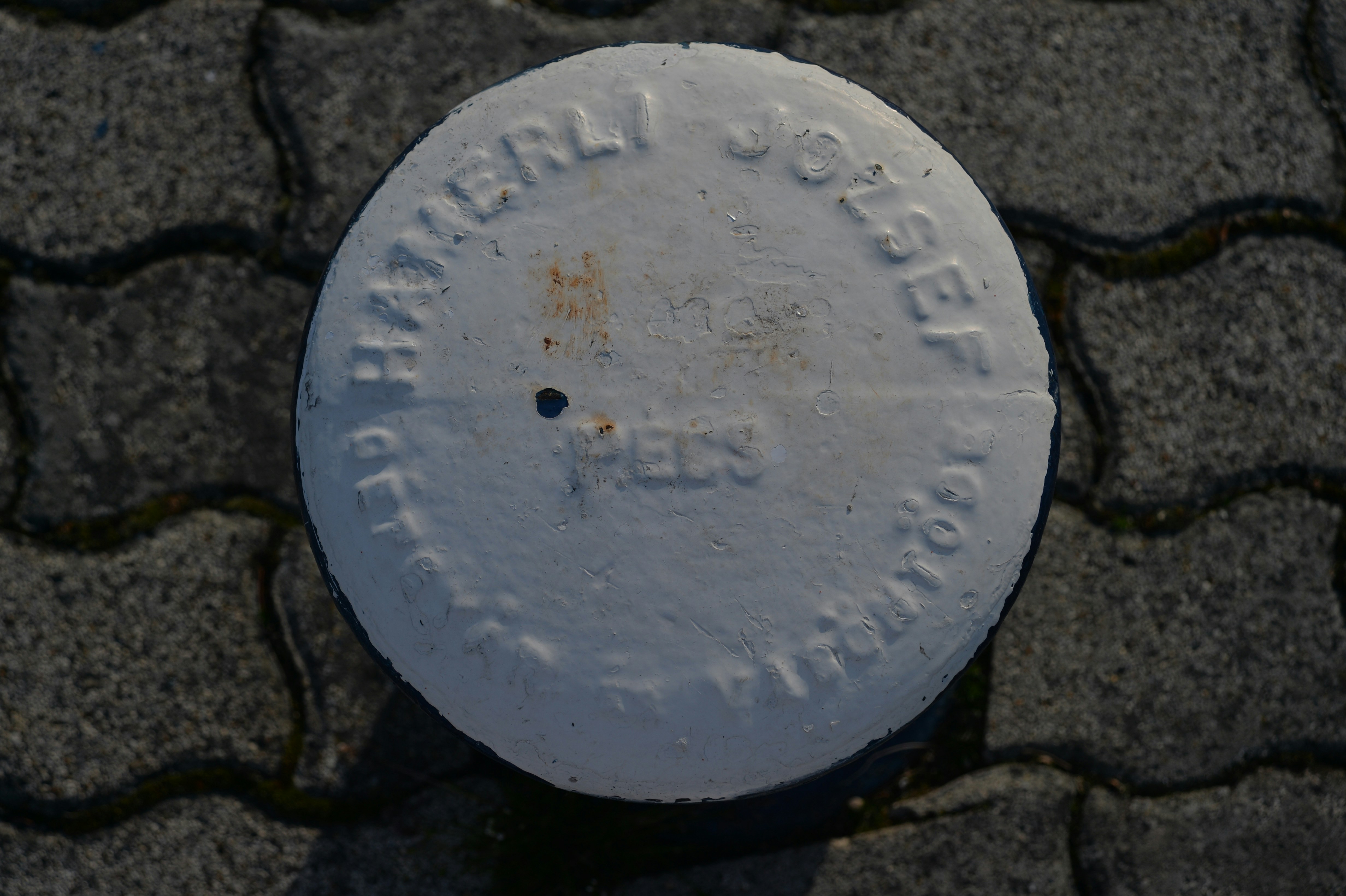 Circular Cap on Weathered Paver: A Quiet Urban Moment