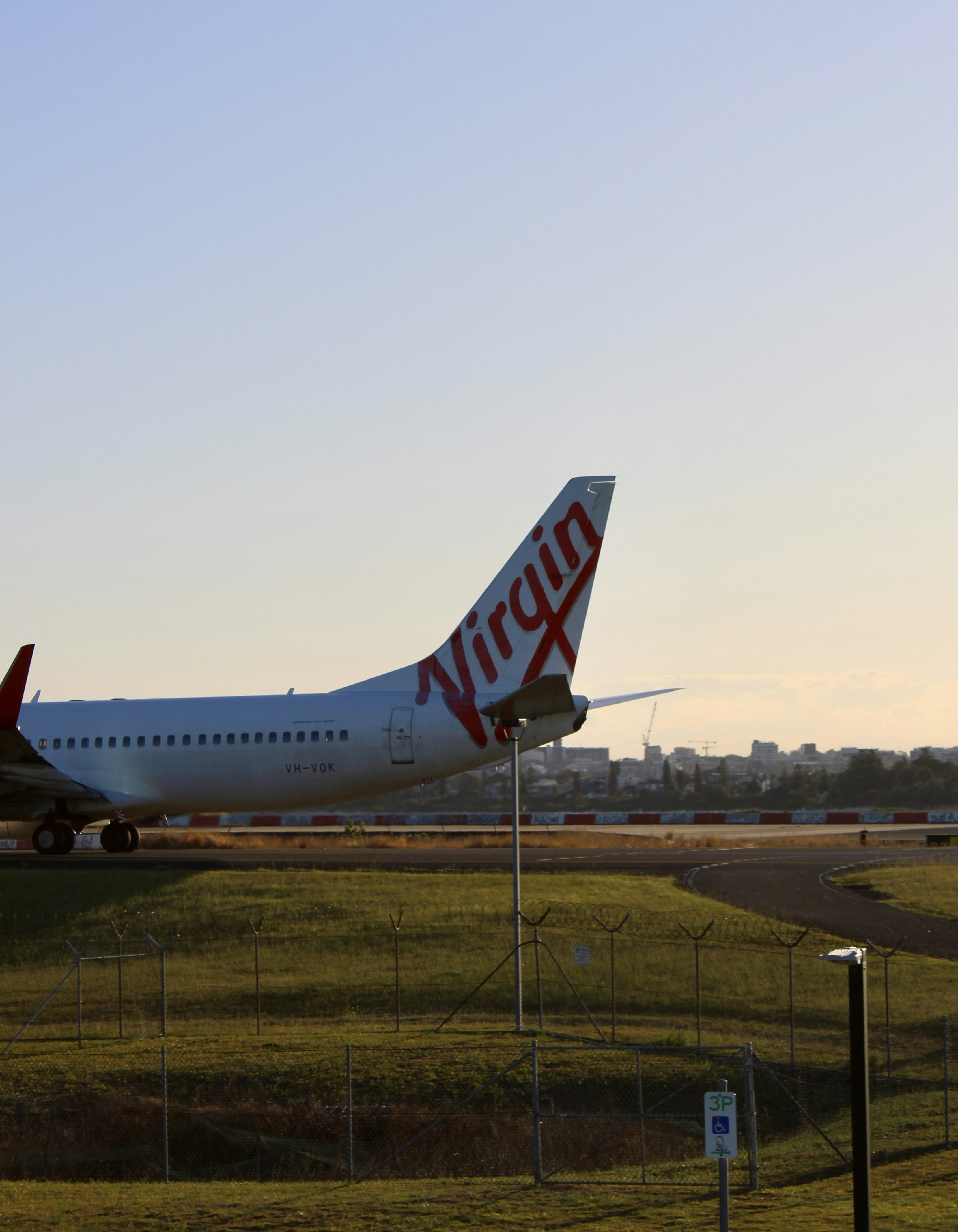 Virgin Australia aircraft preparing for takeoff on a clear evening, showcasing its distinctive livery against a serene backdrop.