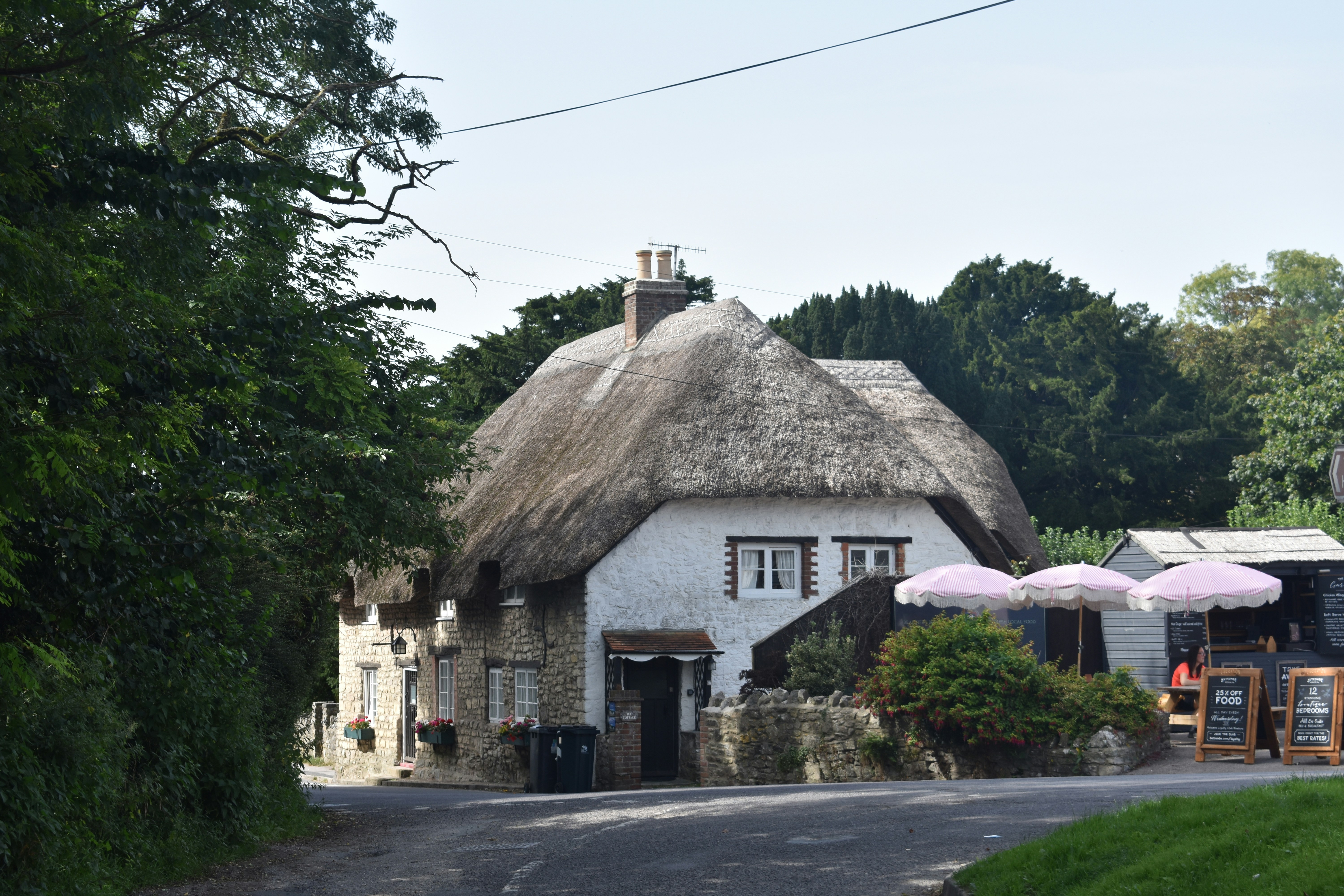 Quaint thatched cottage nestled among greenery, featuring outdoor seating and rustic charm. Perfectly captures a serene countryside vibe.