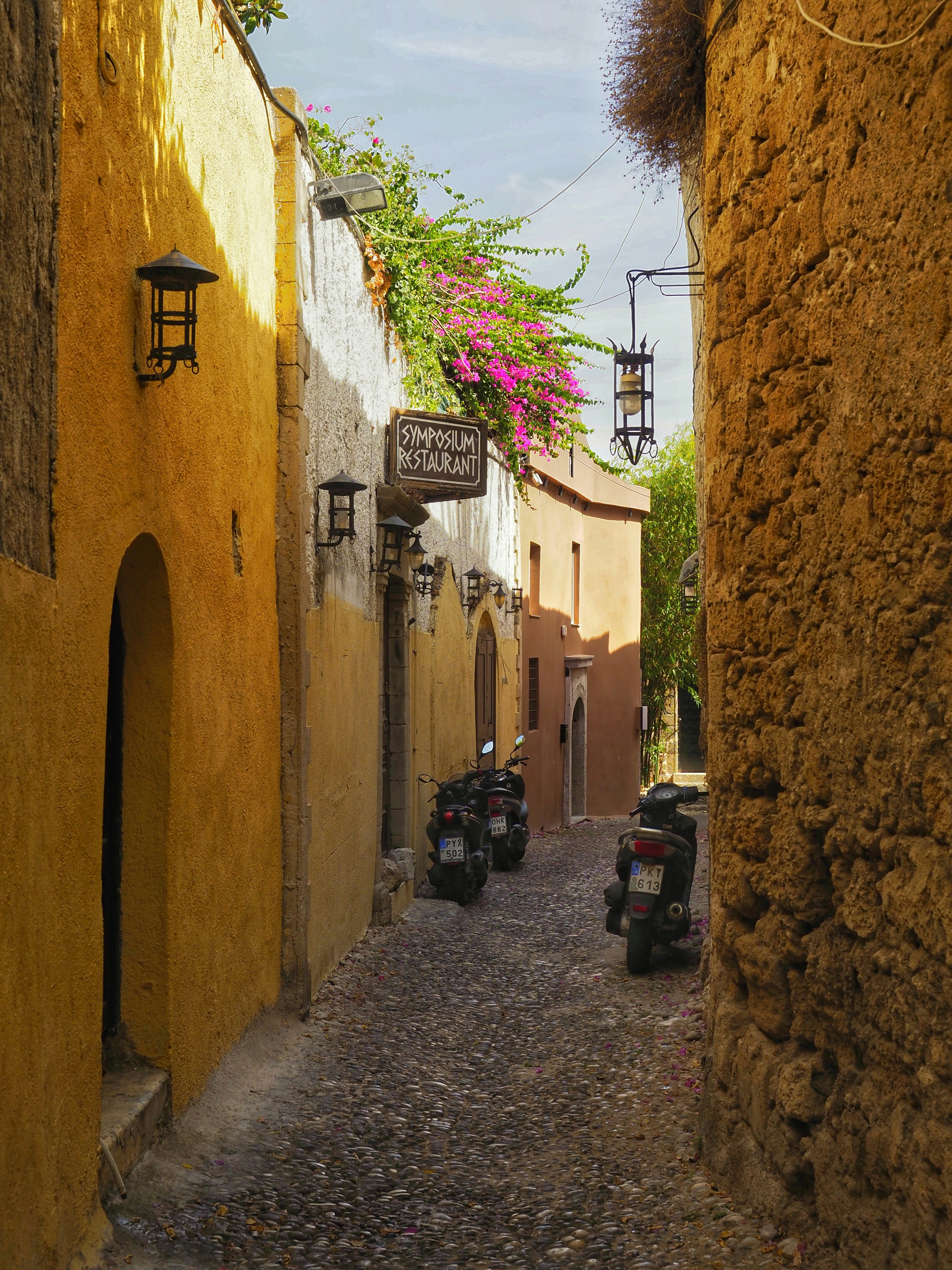 Bougainvillea-Framed Alley of Ochre Walls and Scooters