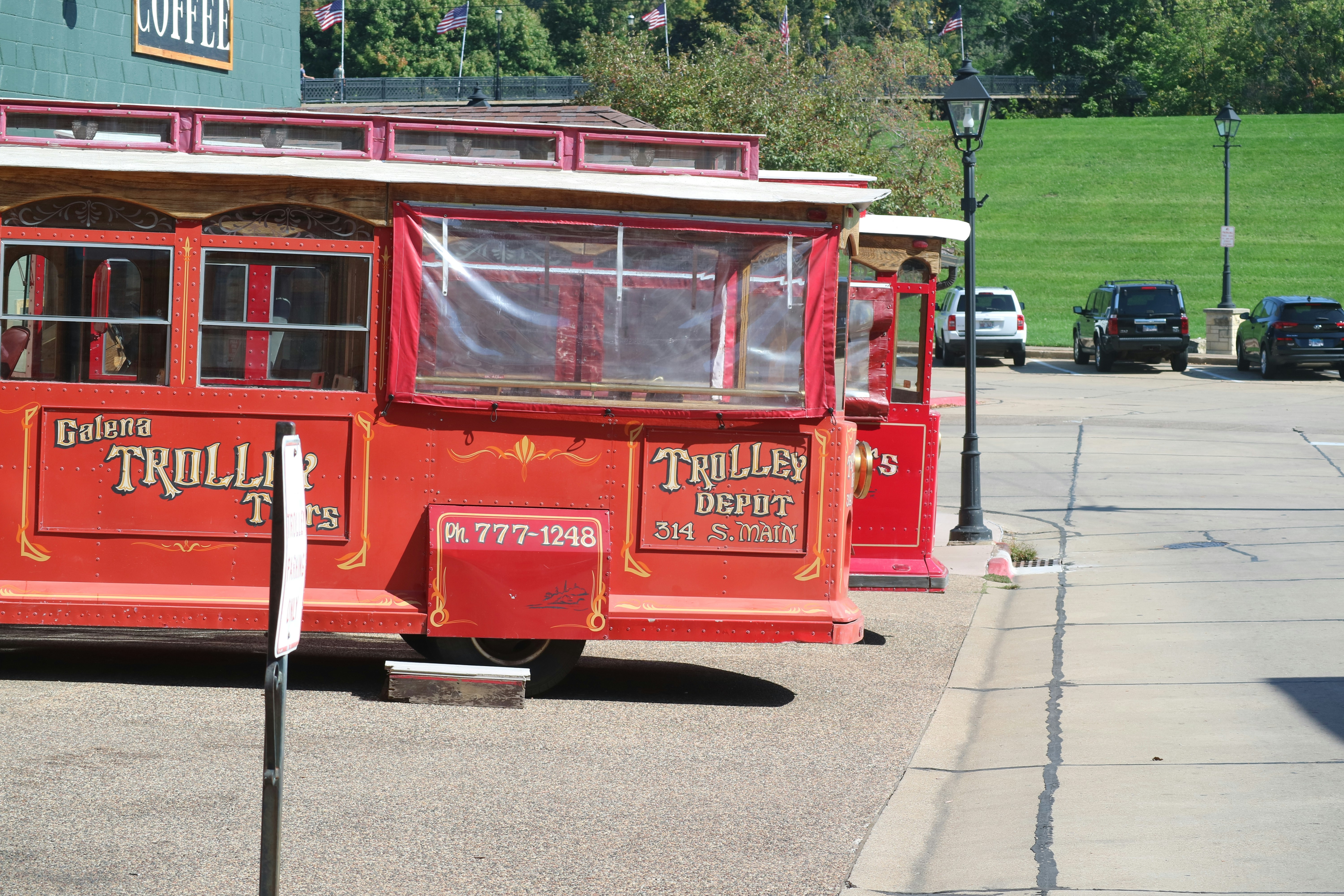 Two Vintage Red Trolley Cars Resting in a Modern Parking Lot