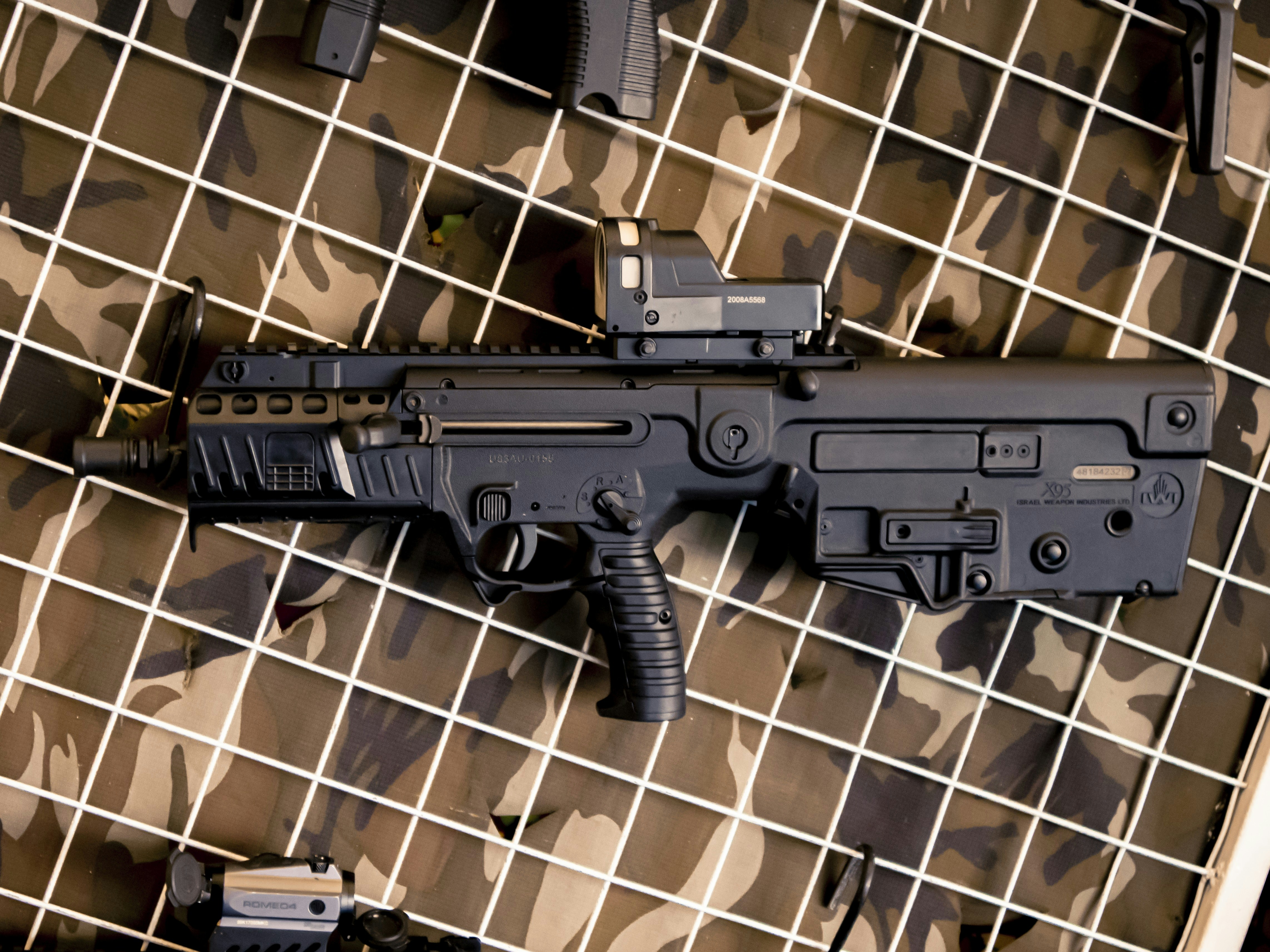 A black rifle laying on top of a camouflage wall photo – Free Weapon ...