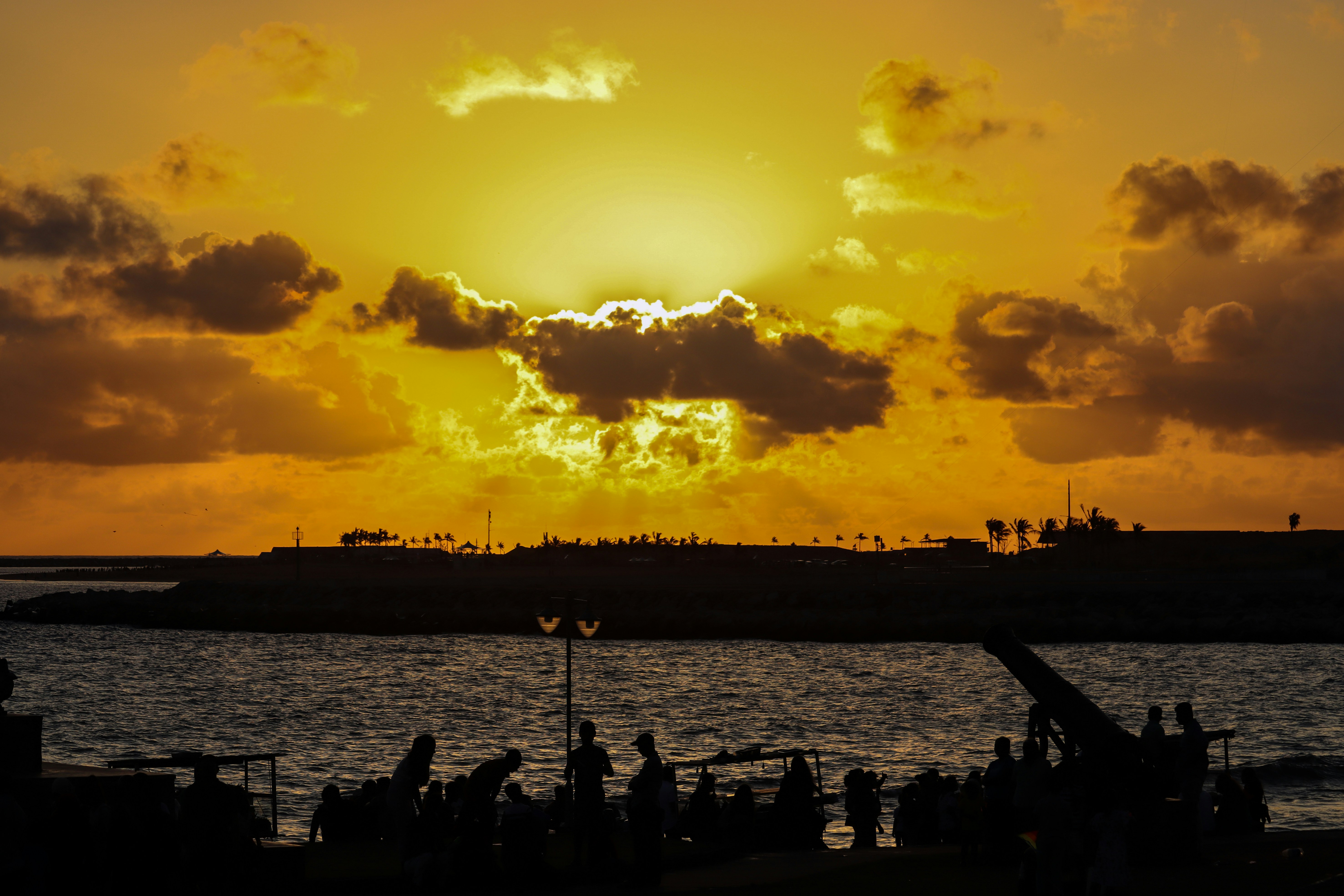 Silhouetted seaside gathering under a molten sunset