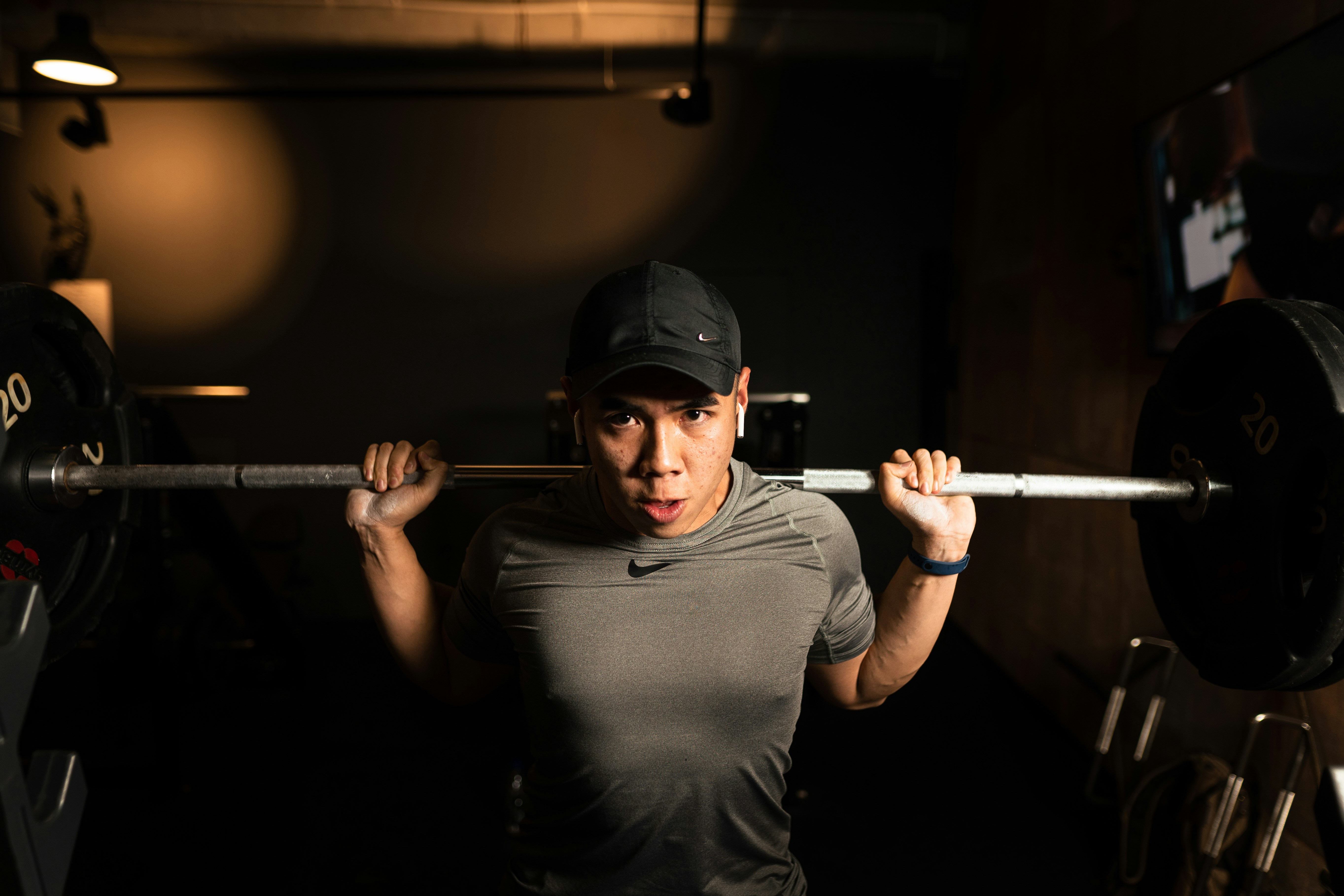 A woman lifting a barbell in a dark room photo – Free Gym Image on Unsplash