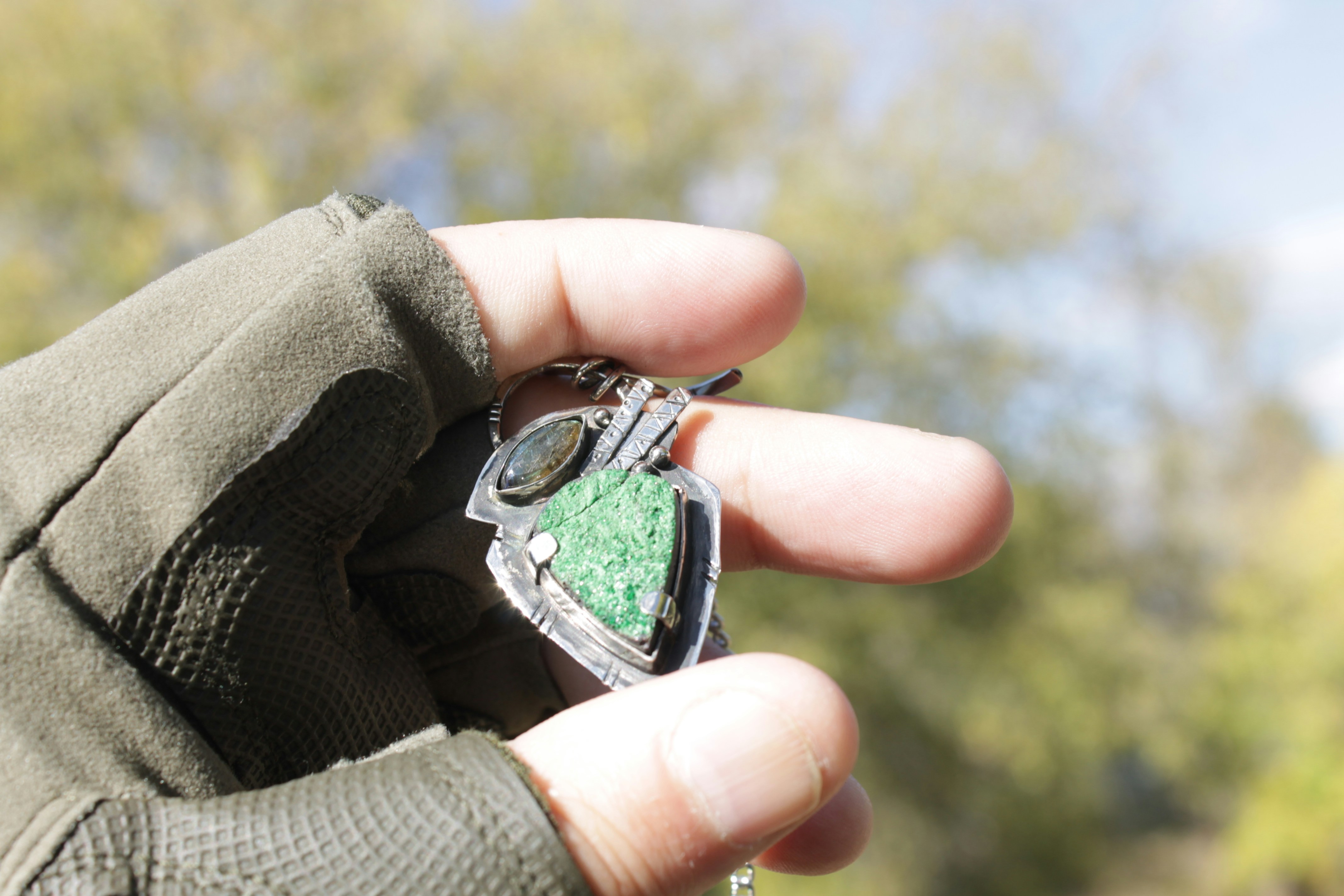 Glinting Charms: A Green-Glazed Pendant Between Fingers