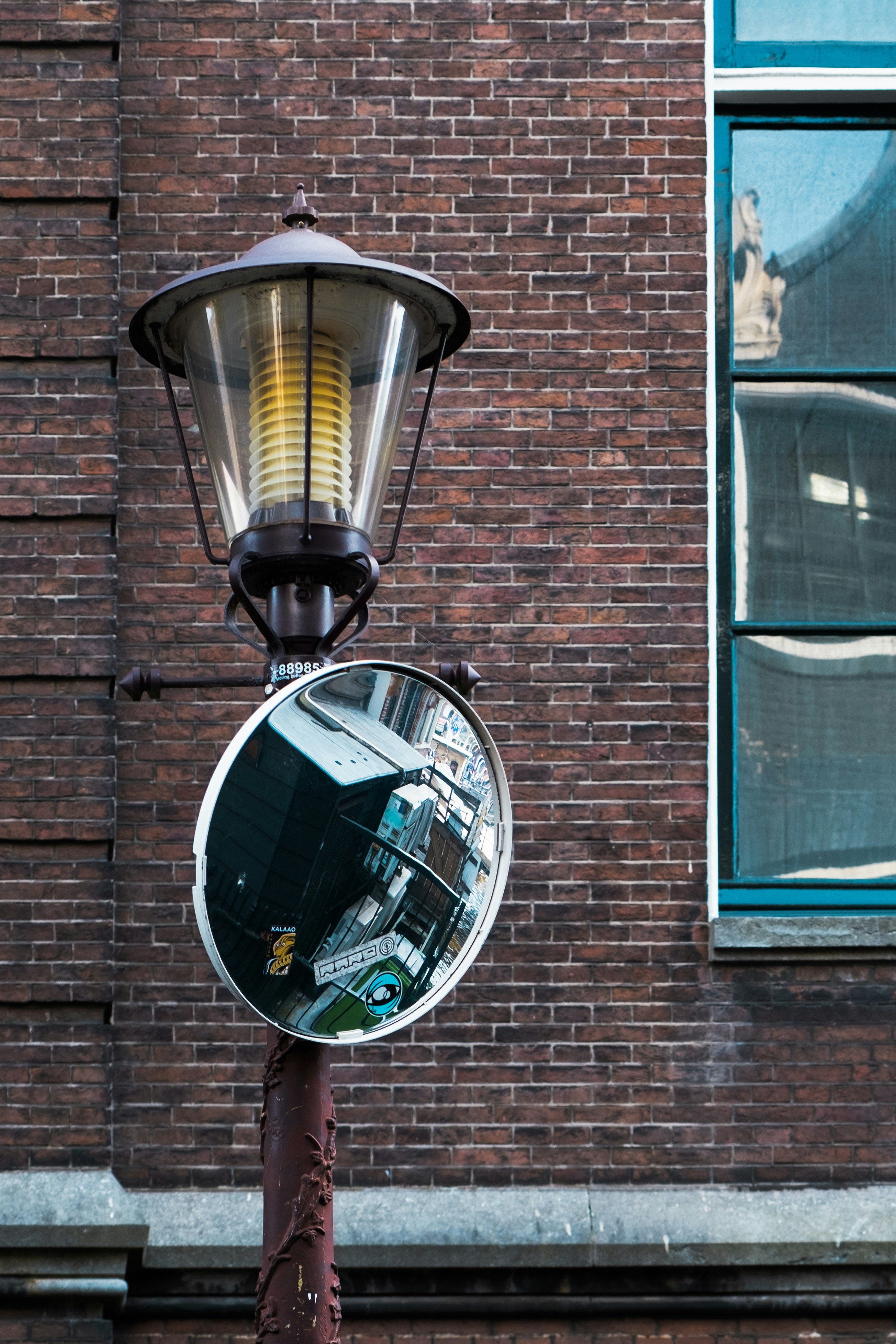 Lantern, Brick, and a Circular Mirror: A Quiet City Reflection
