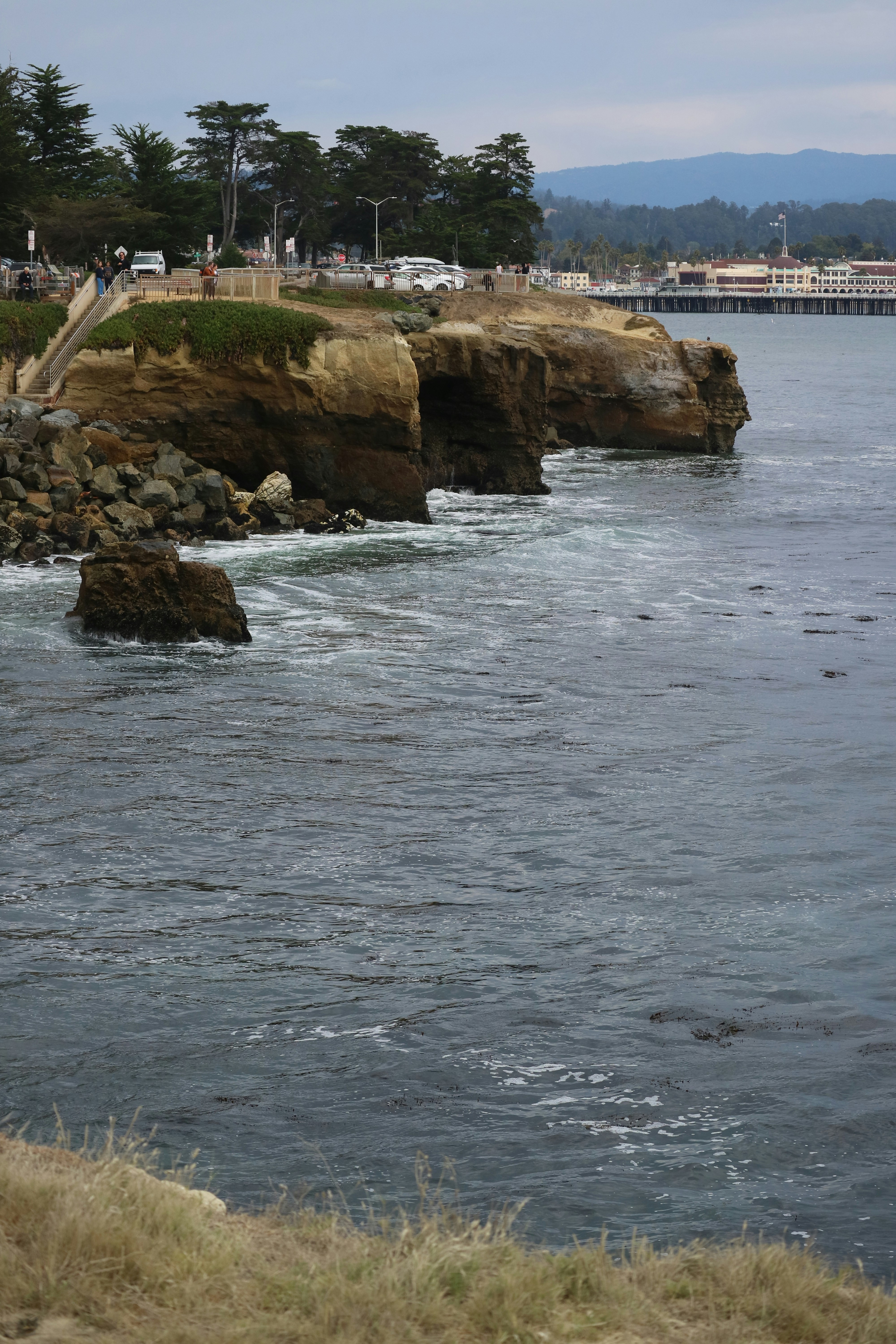 Promenade Over the Cliff: Quiet Harbor View Beyond the Rocks