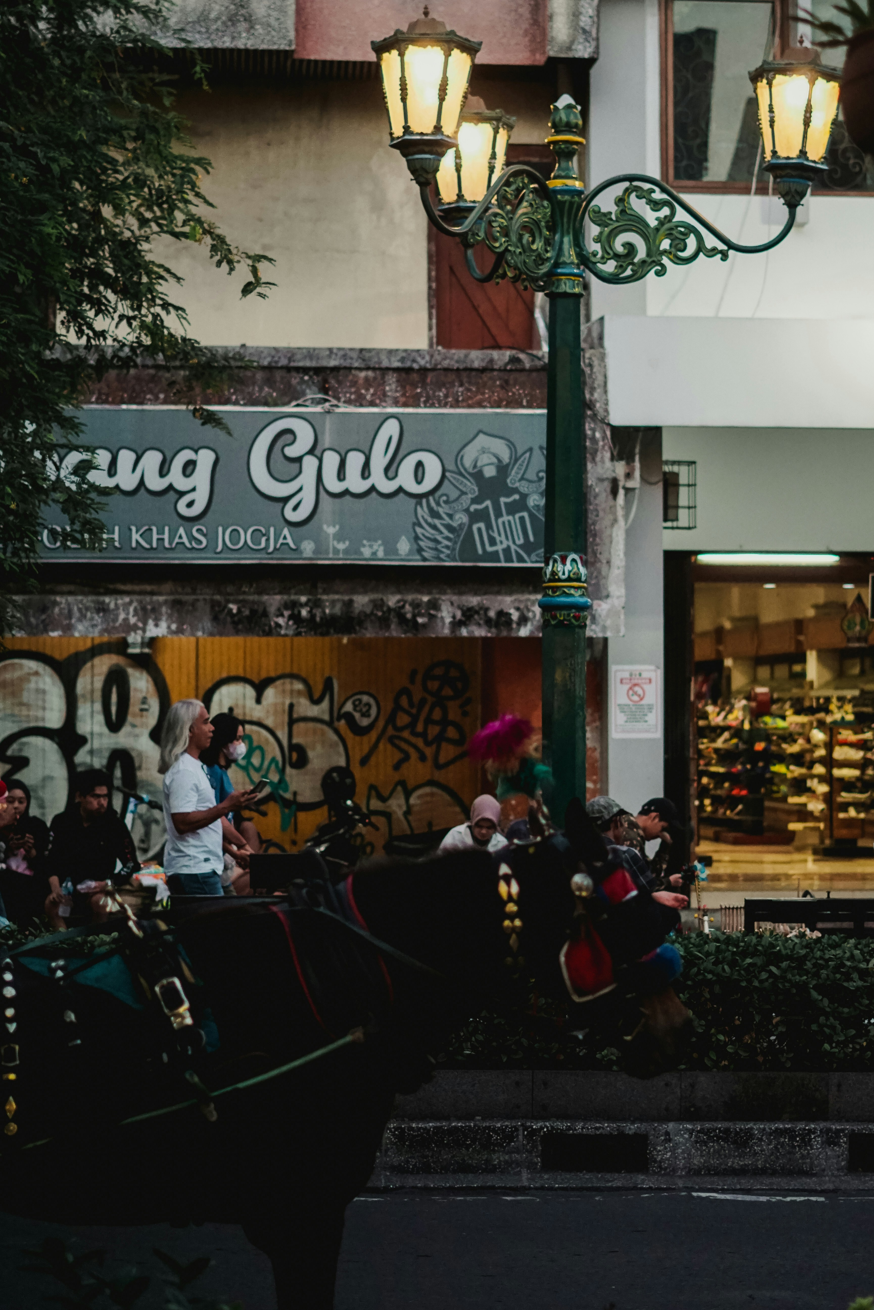 Gaslamp in Focus: An Ornate Lantern Framing a Graffiti-Strewn Jogja Street