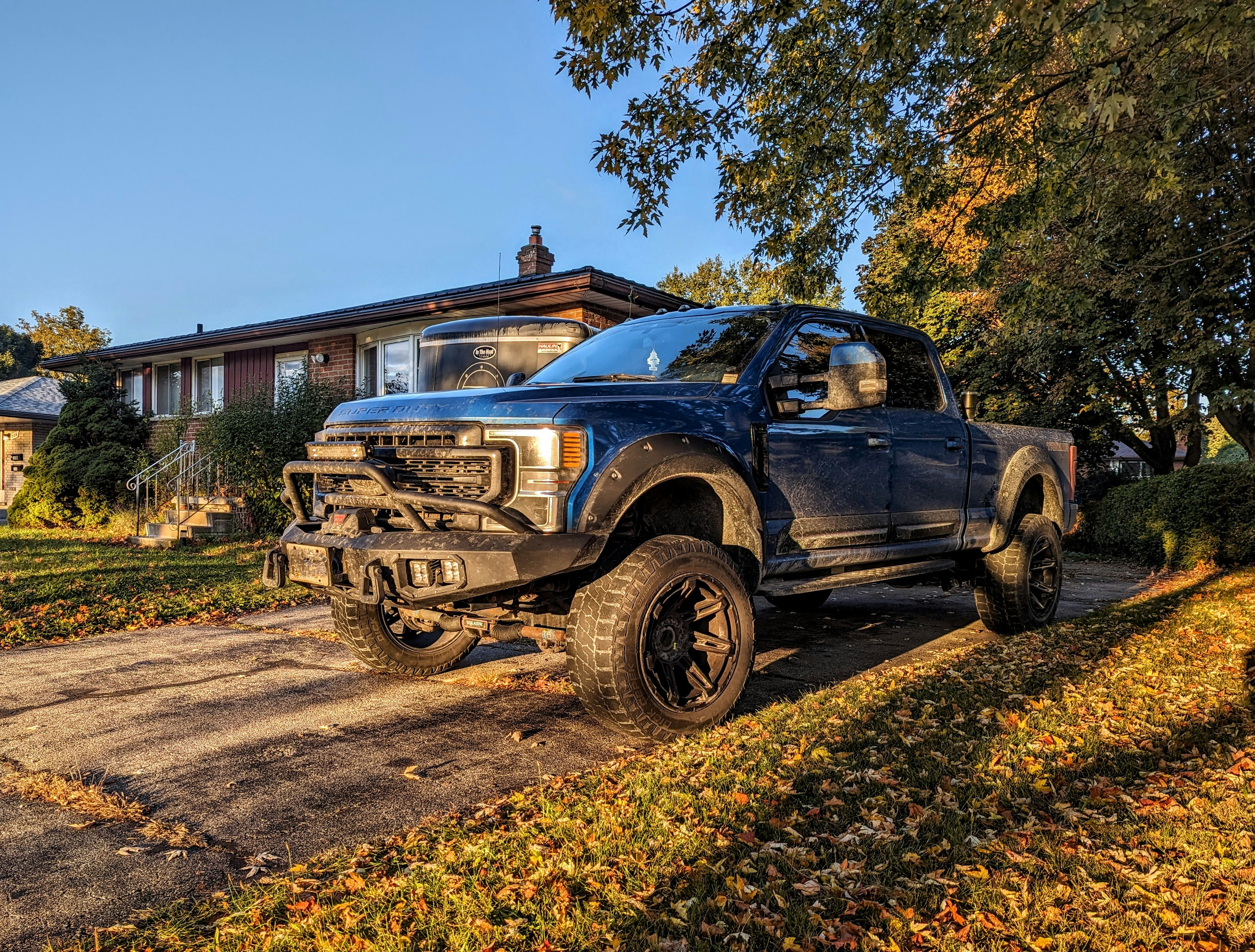 Autumn Light Illuminates a Mud-Splashed Blue Pickup on a Quiet Suburban Driveway