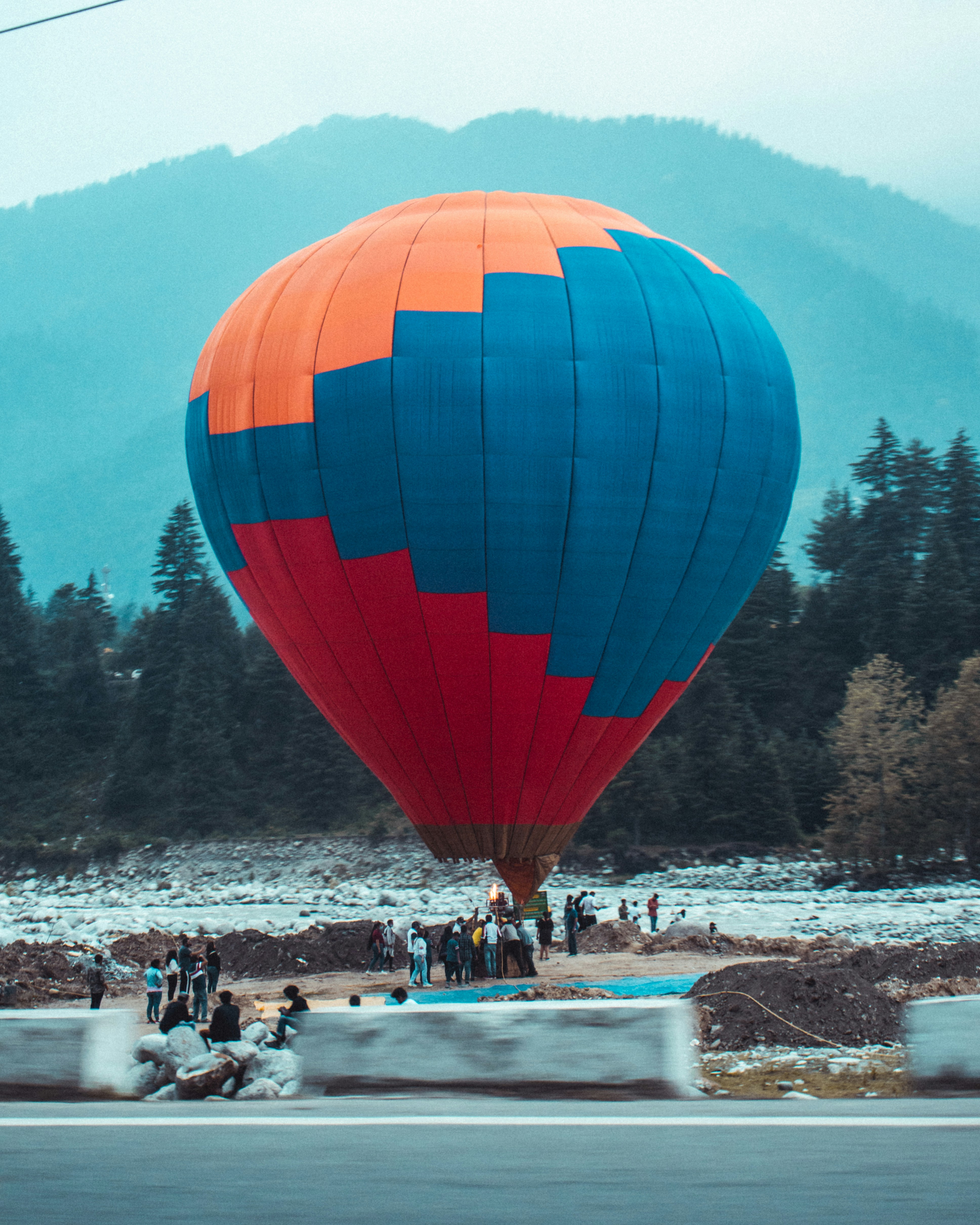 Floating Beacon: A Red-Blue Balloon Rises Over a Riverbank Crowd