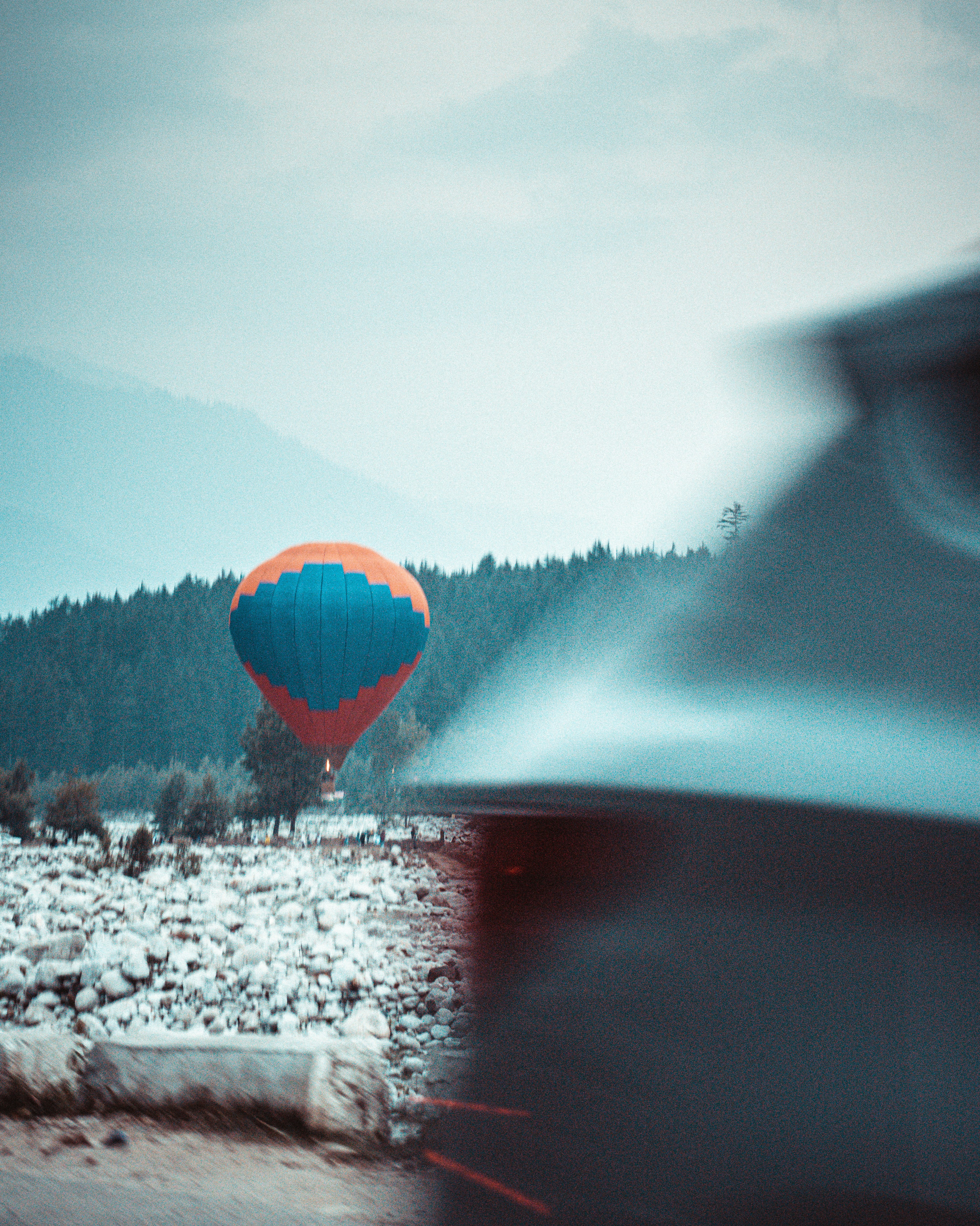 Orange-and-Blue Balloon Drifts Over a Pebble Riverbank at Dawn