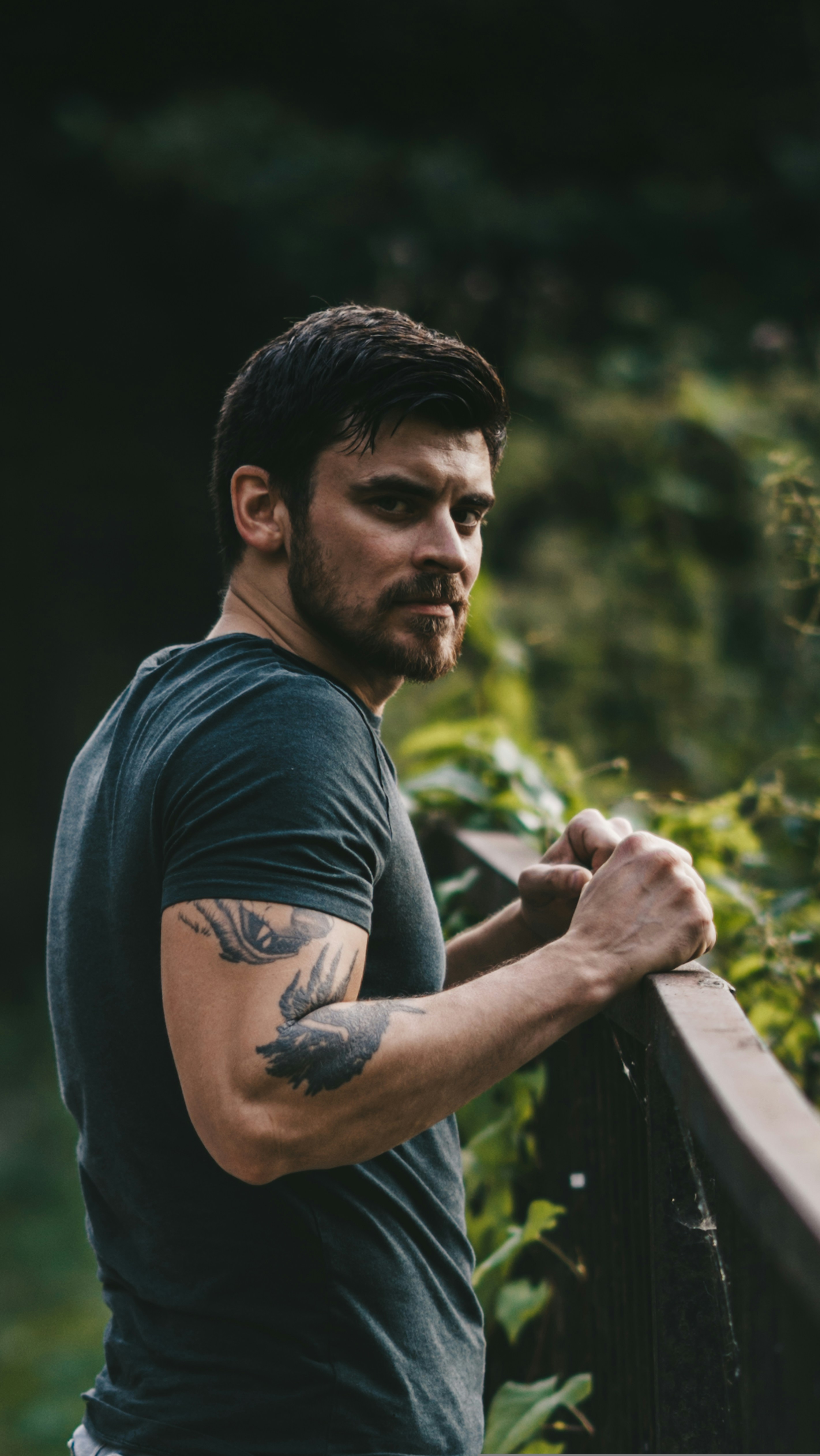 A man with a tattoo on his arm leaning on a rail photo – Free Fashion ...
