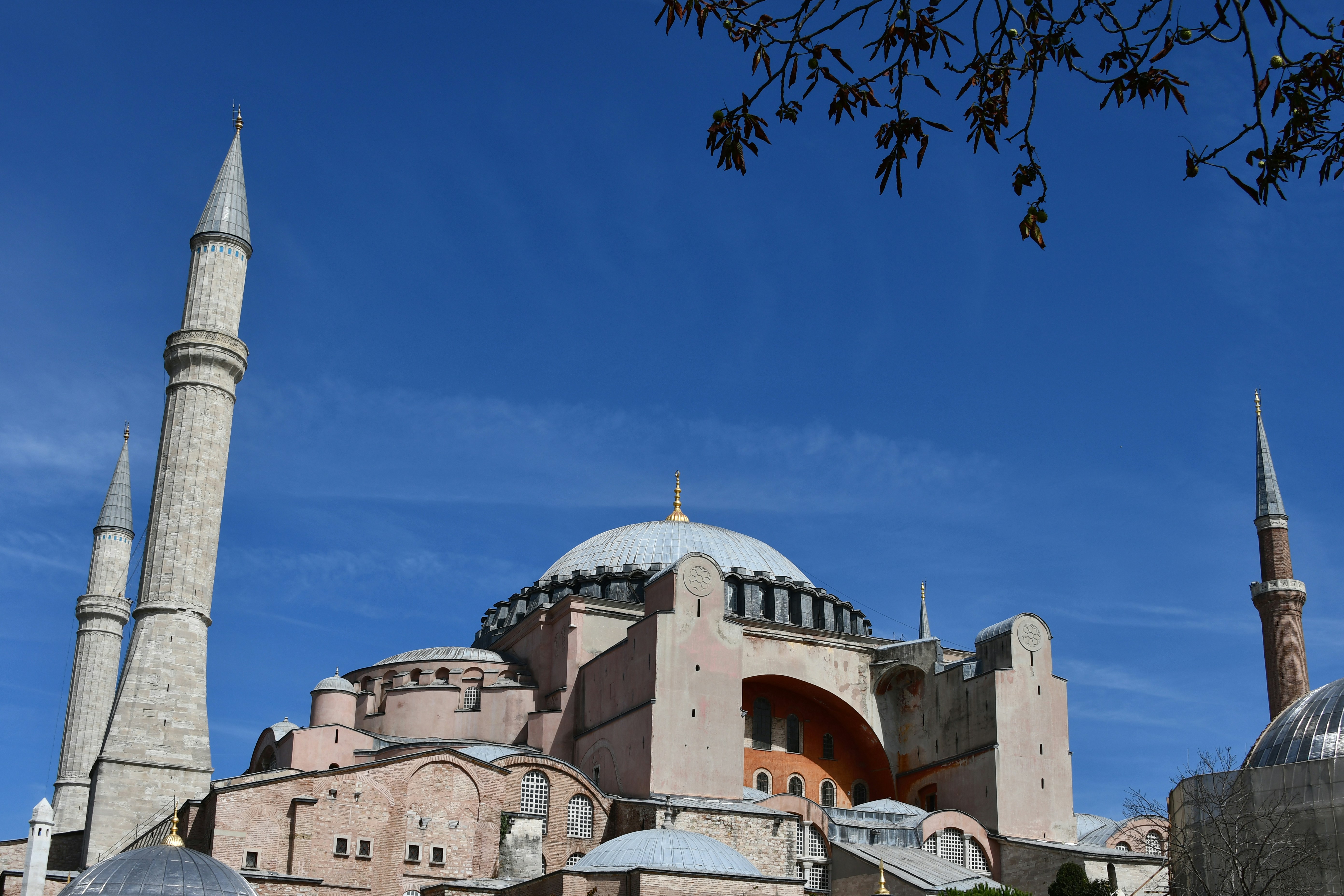 Historic dome and minarets of a grand architectural structure against a bright blue sky.