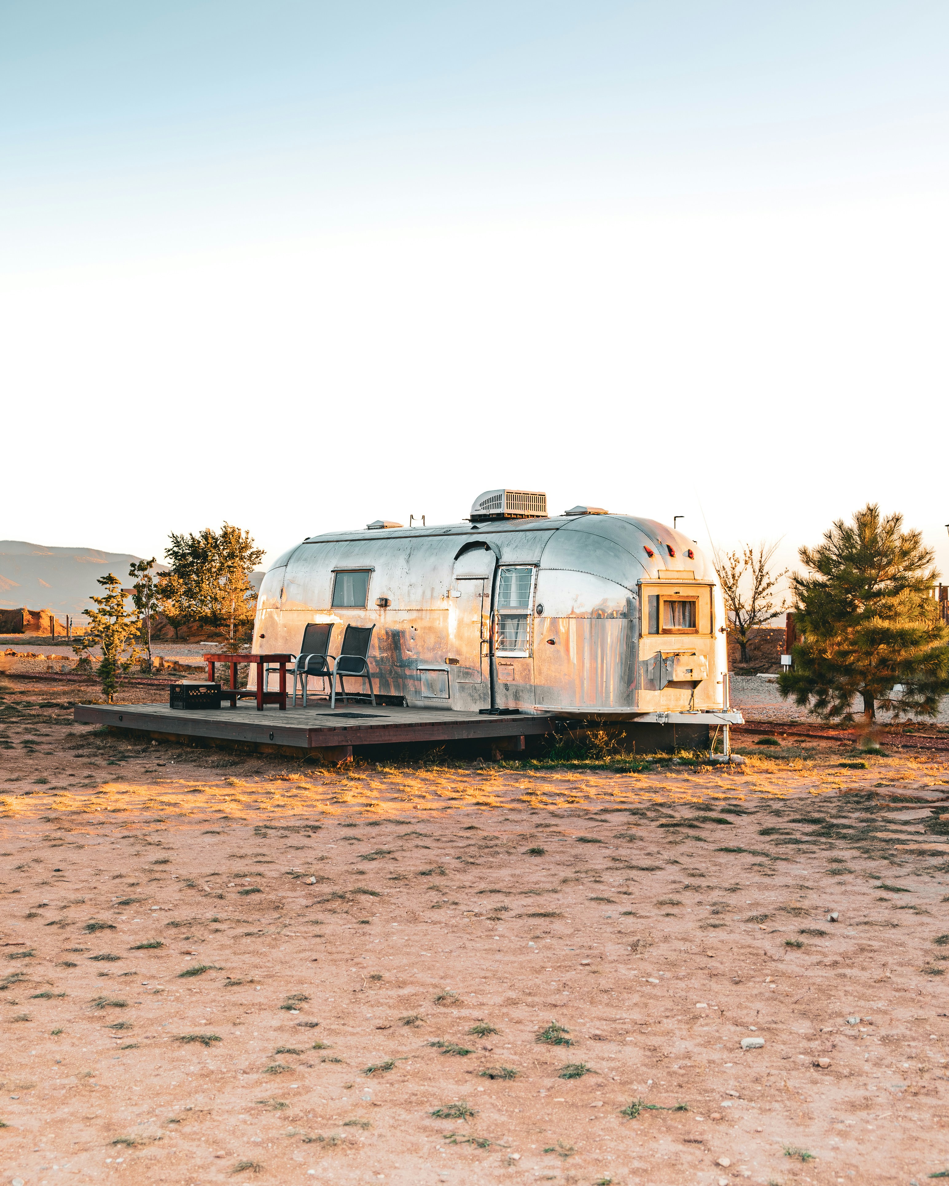 A silver trailer parked in a field next to trees photo – Free Usa Image ...