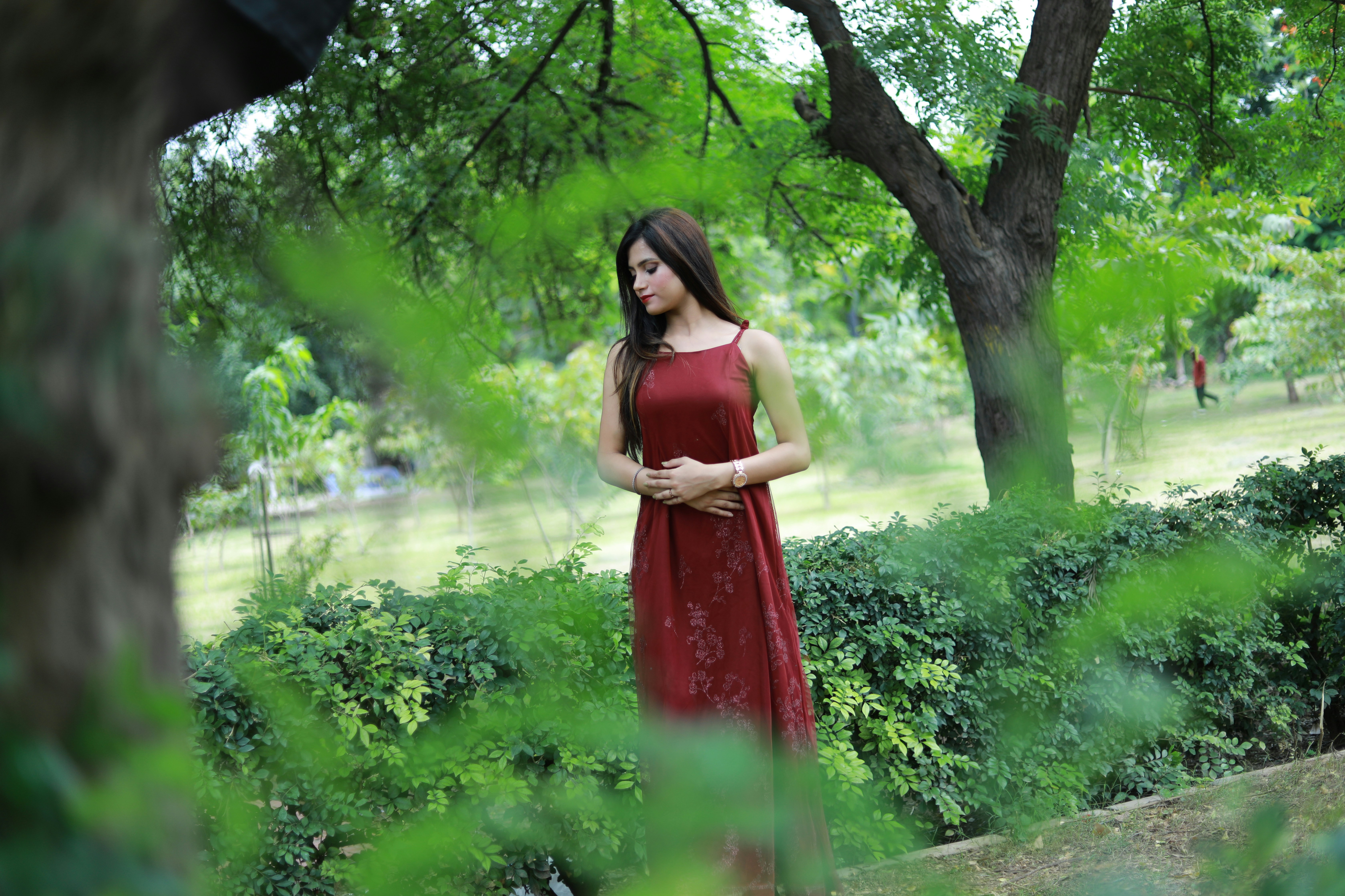 A woman in a red dress standing under a tree photo – Free Portrait ...