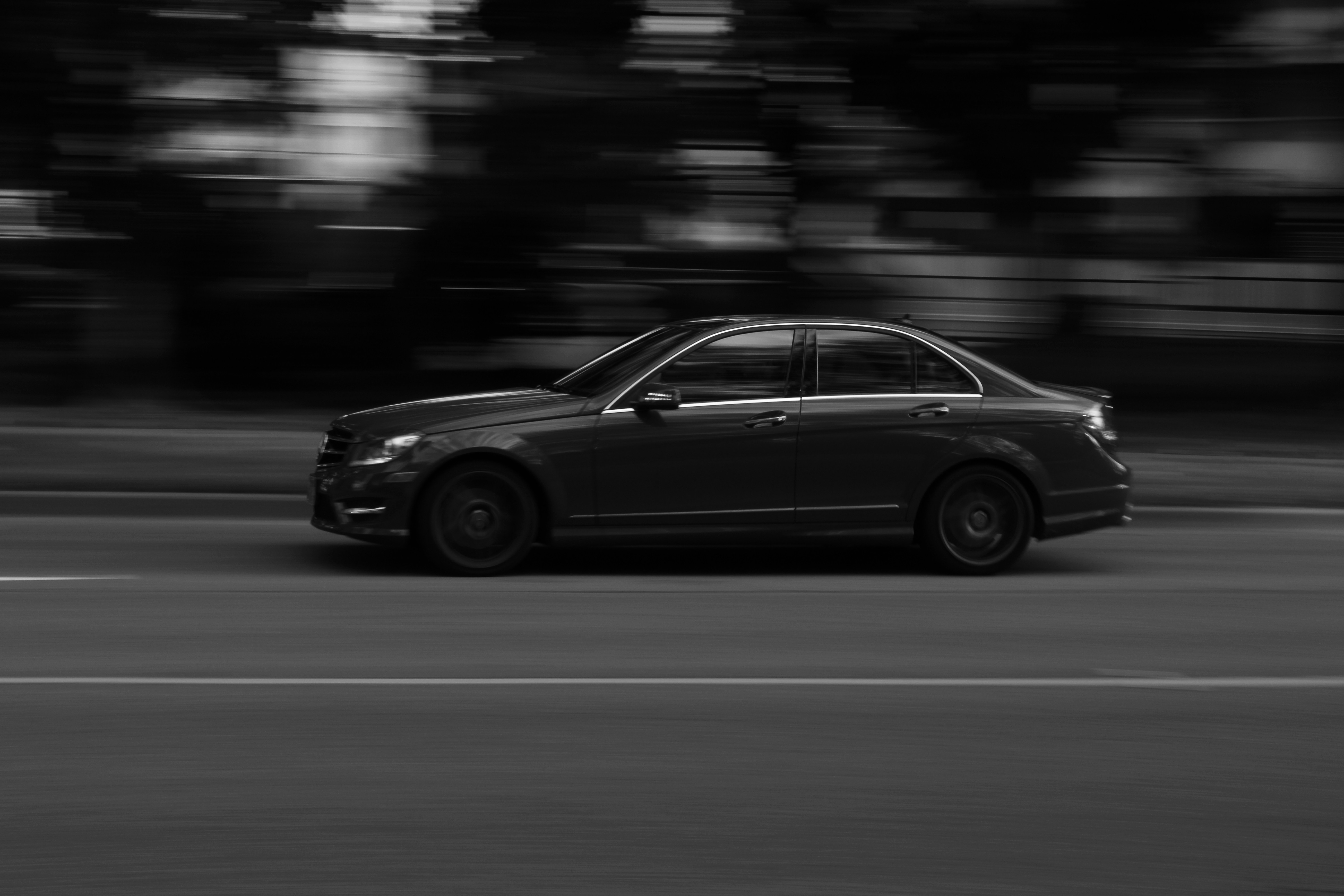 A black and white photo of a car driving down a street photo – Free ...