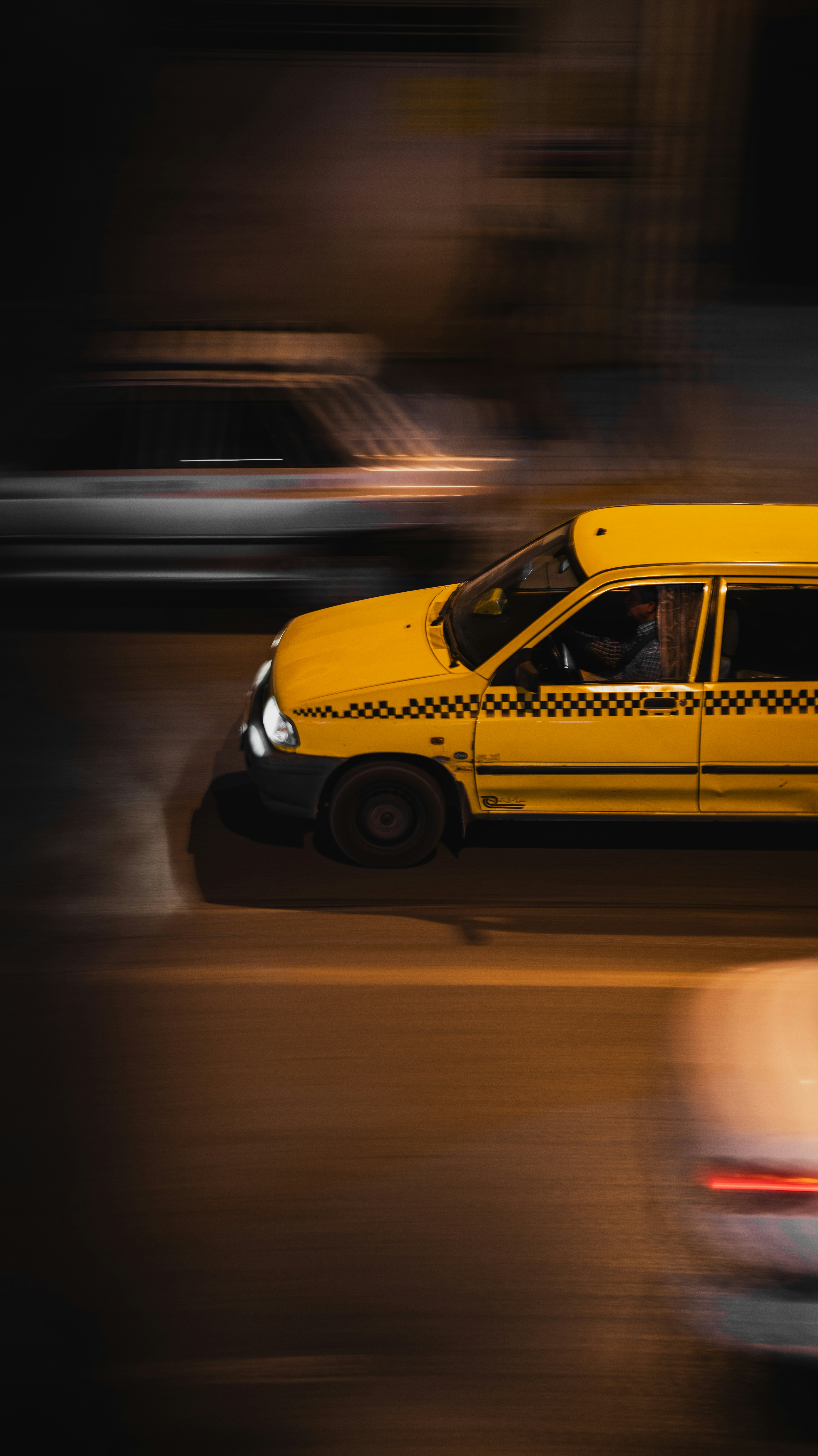 A yellow taxi cab driving down a street at night photo – Free Car Image ...