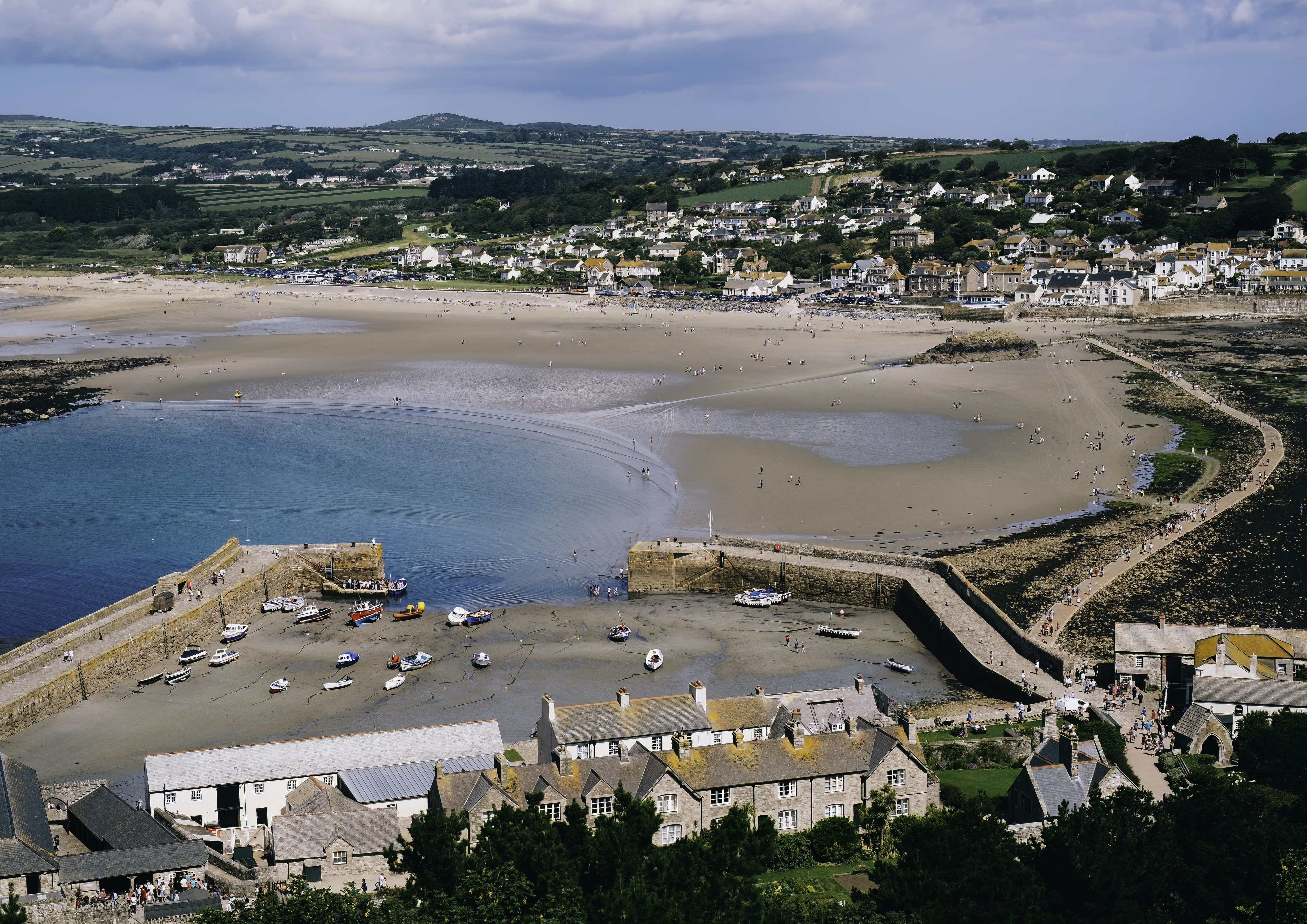 View of Marazion's sandy shores and harbor from St Michael's Mount, with rolling hills in the background.
