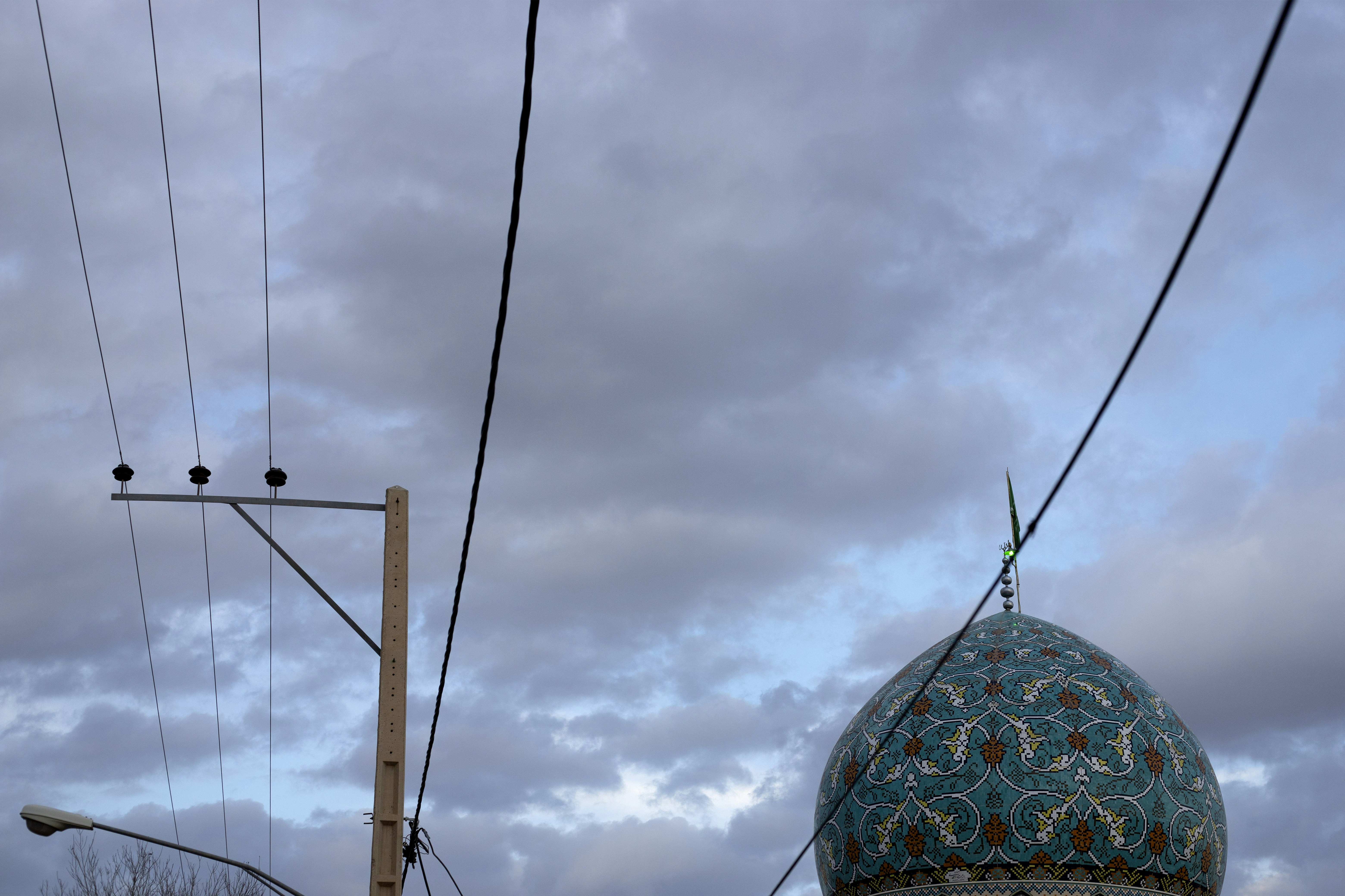 Under the Dome: Turquoise Minaret and Utility Lines Against a Weeping Sky