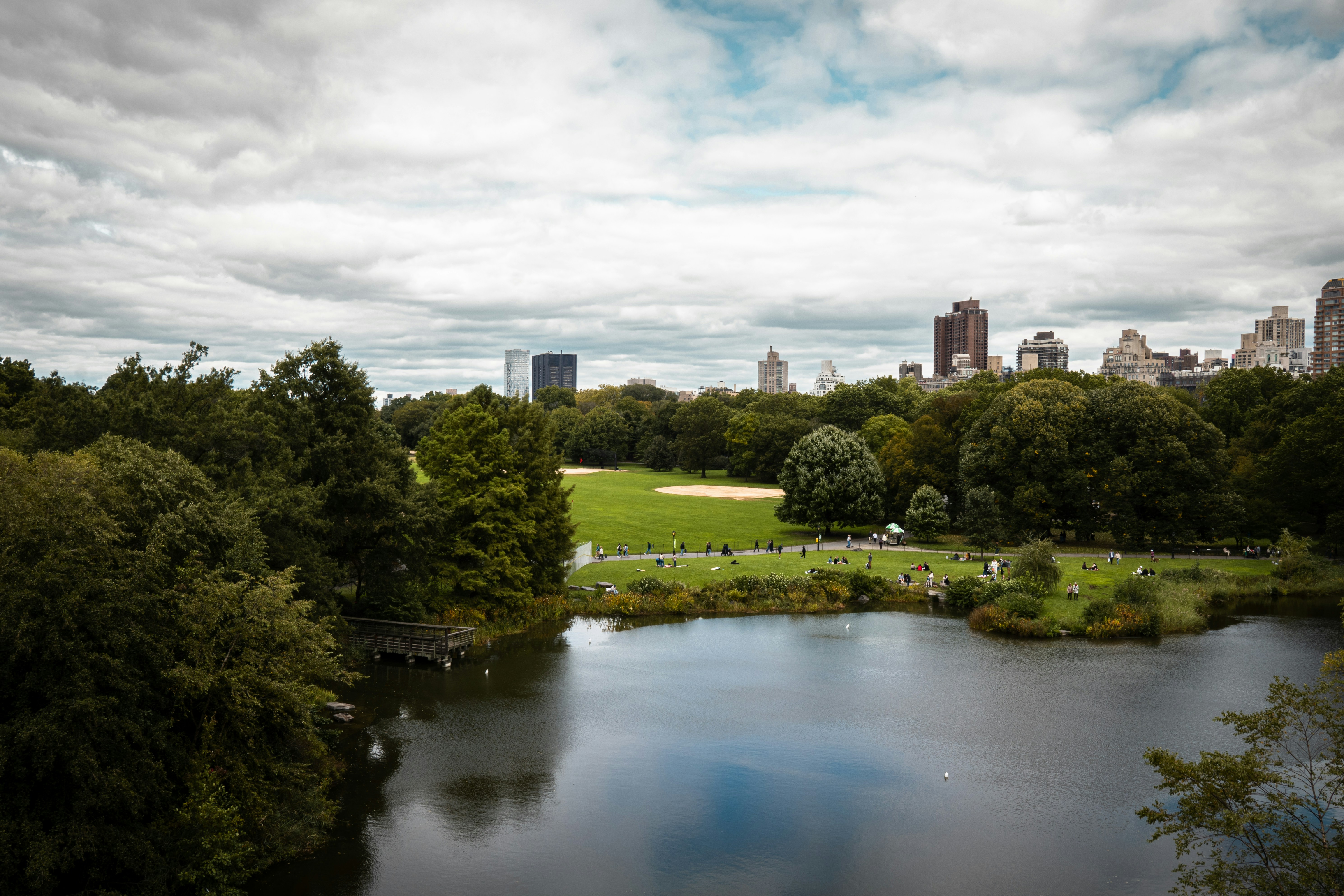 A lake in a park with a city in the background photo – Free Central ...