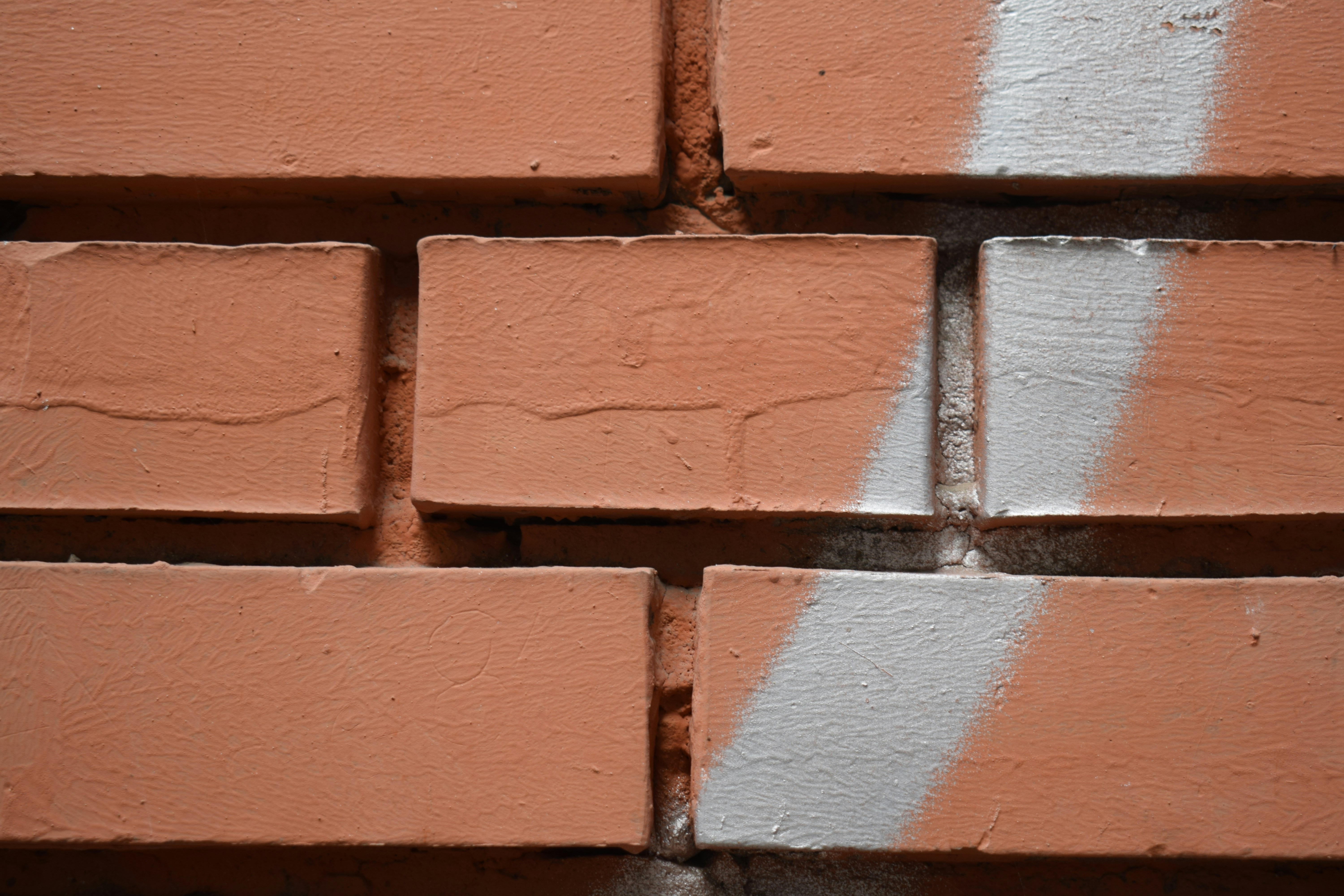 Brickwork in Focus: A Diagonal White Graffiti Slice Across Warm Tiles