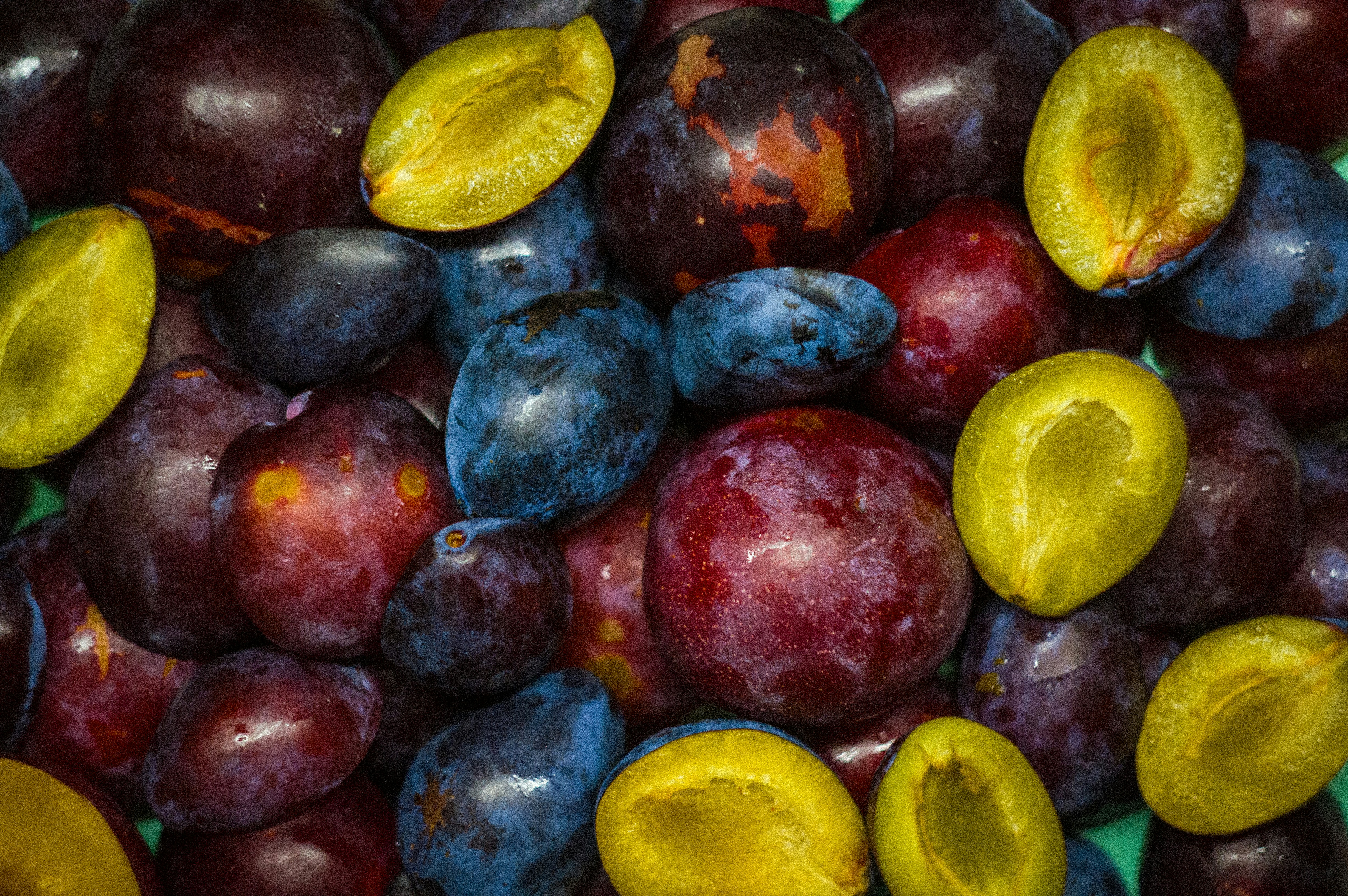 A pile of plums and plums with one cut in half photo – Free Fruit Image ...