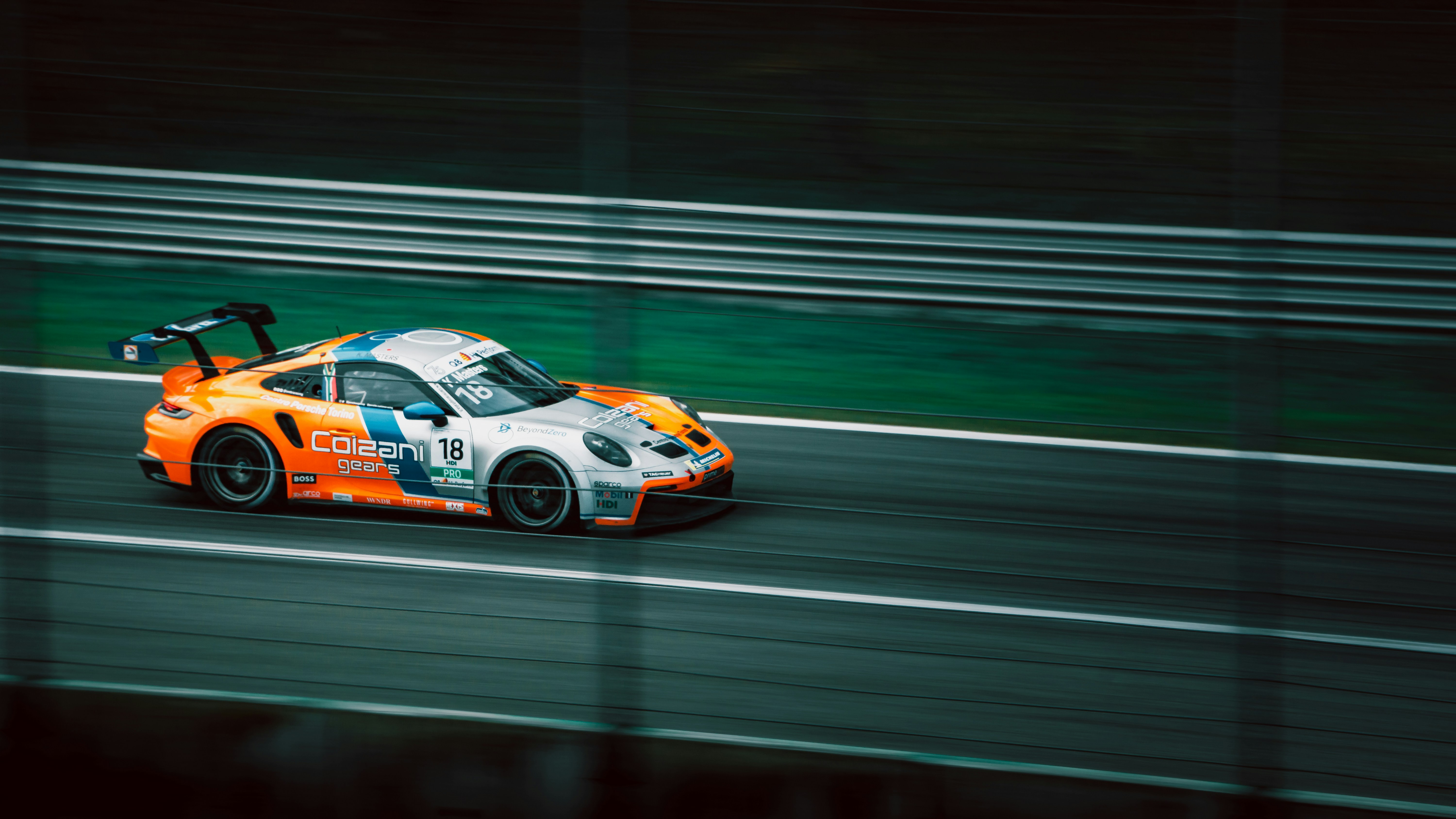 An orange and white car driving down a race track photo – Free ...