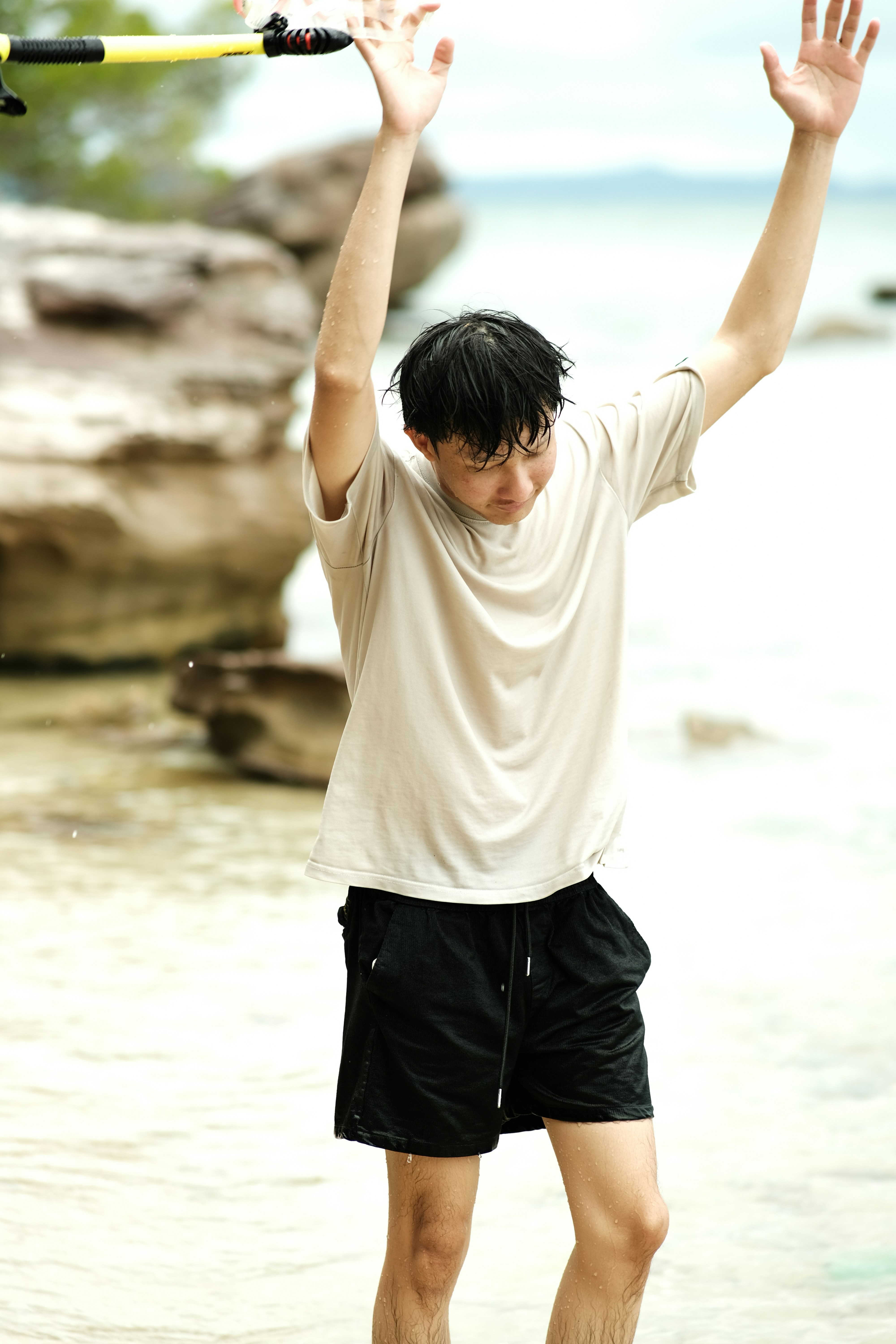 Lift-off on the Shore: Man in Beige Tee Elevates Ambition by the Sea