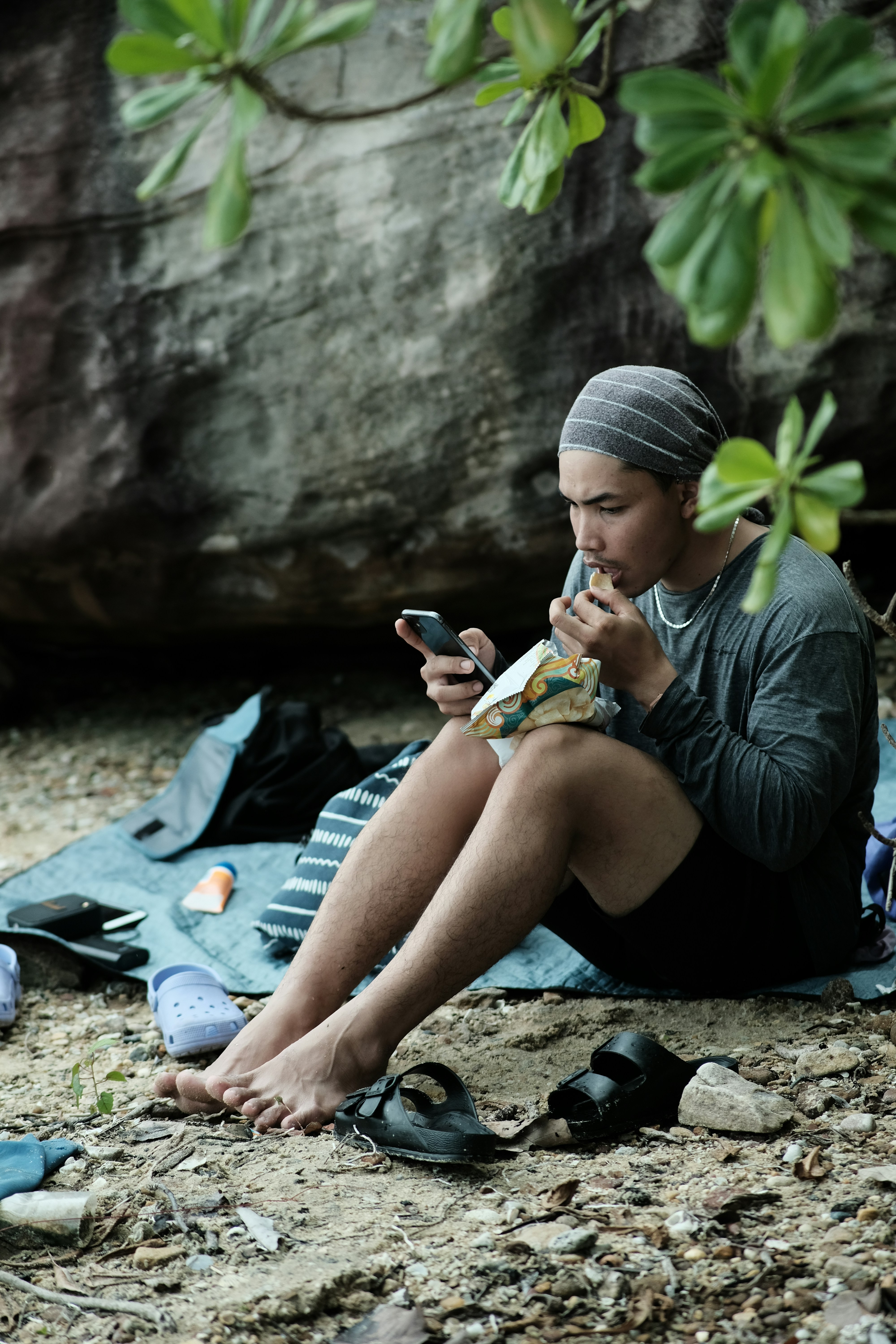 Quiet Break Under the Cliff: A Moment of Snack and Screen