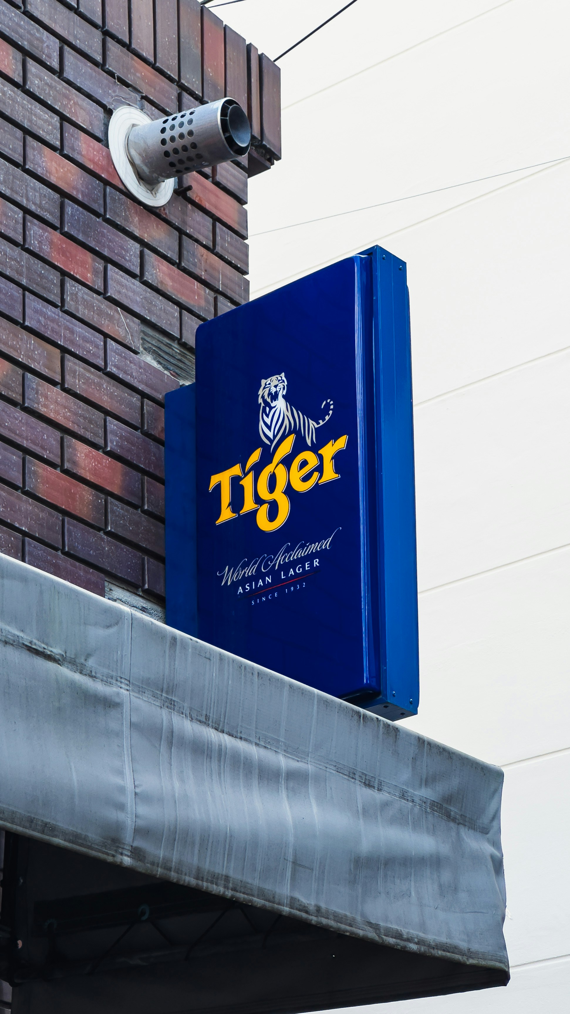 A blue sign hanging off the side of a brick building photo – Free Sign ...