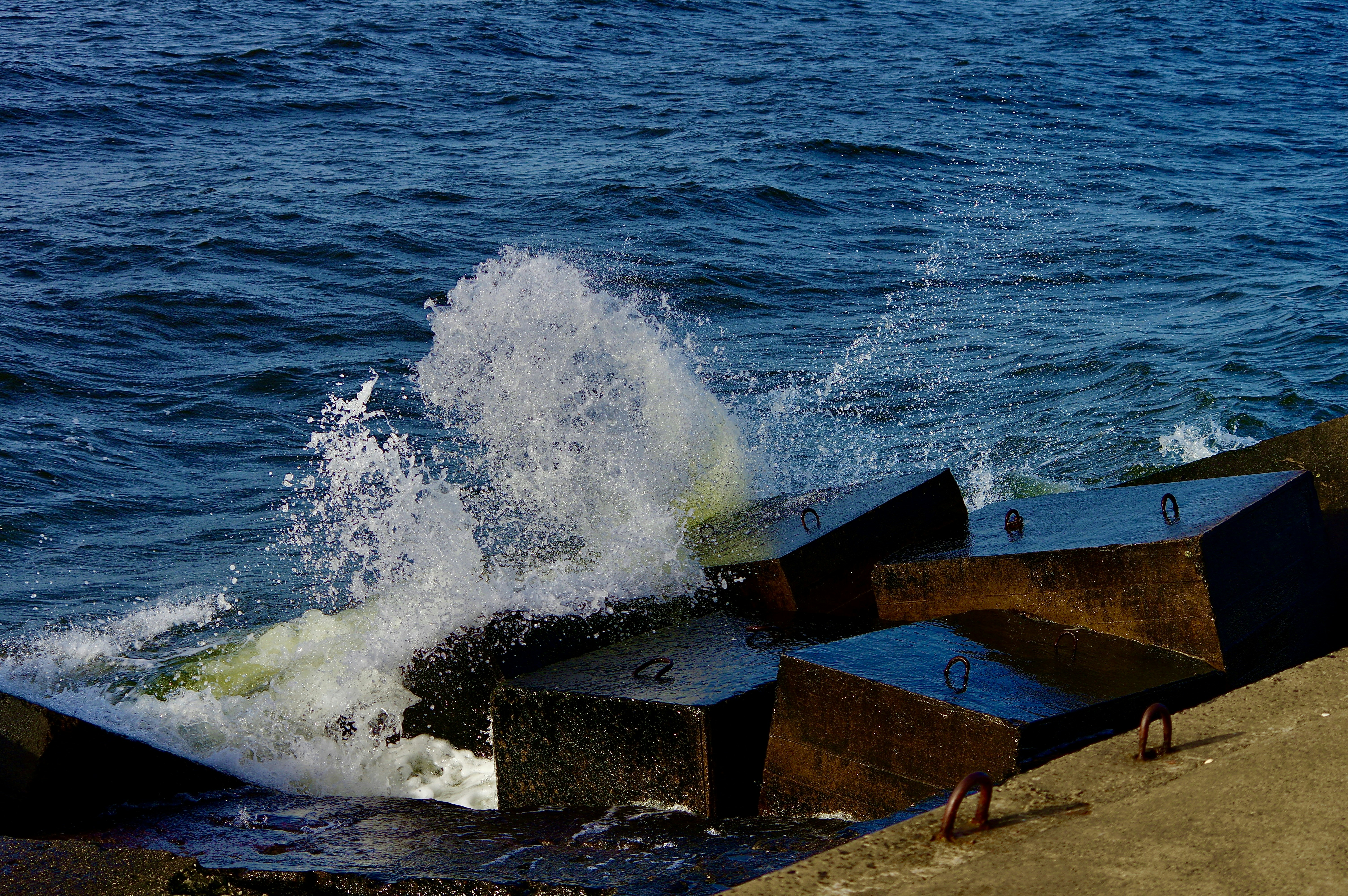 Cobalt Wave Clashes with Weathered Breakwater Blocks