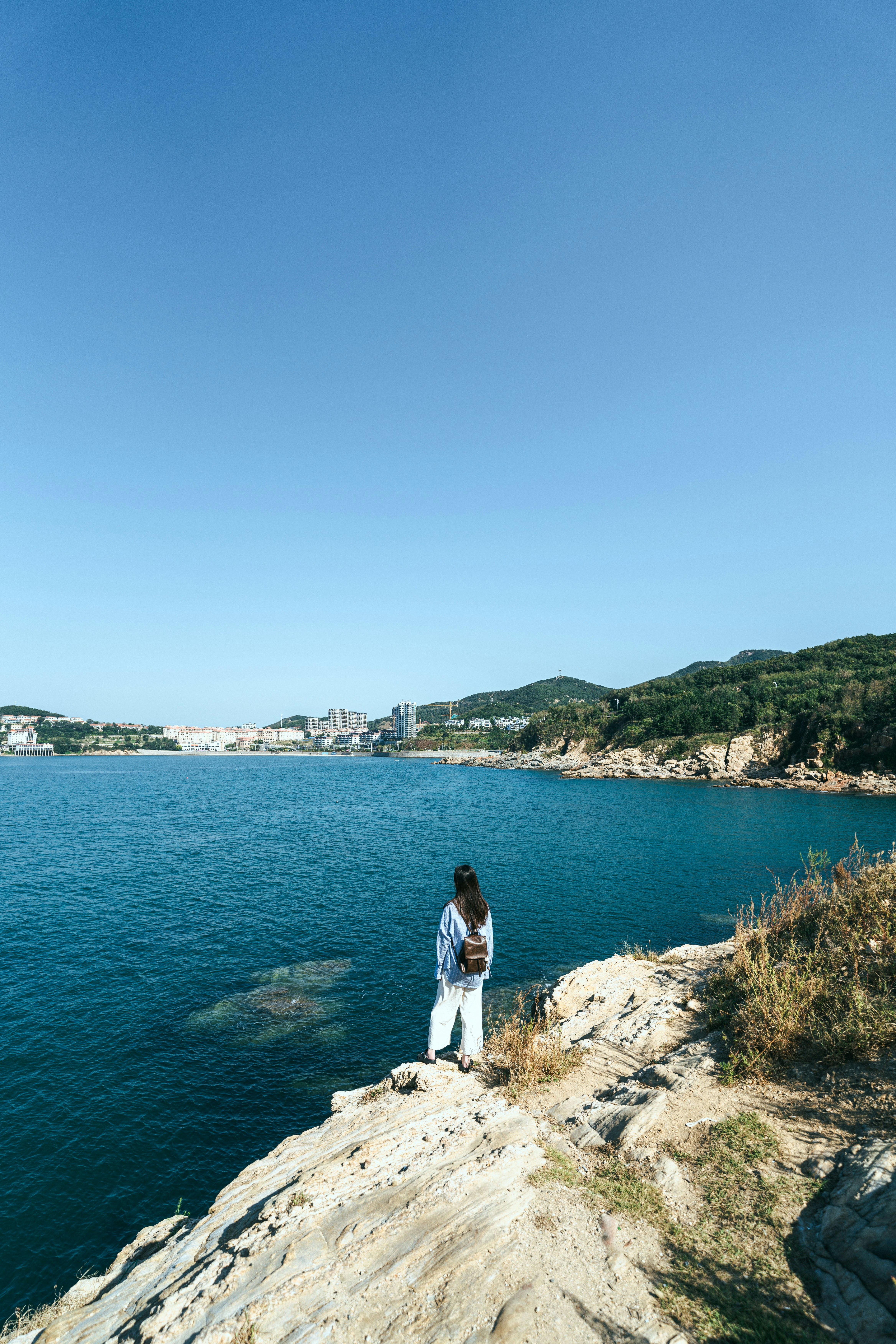 A person standing on a cliff overlooking a body of water photo – Free ...