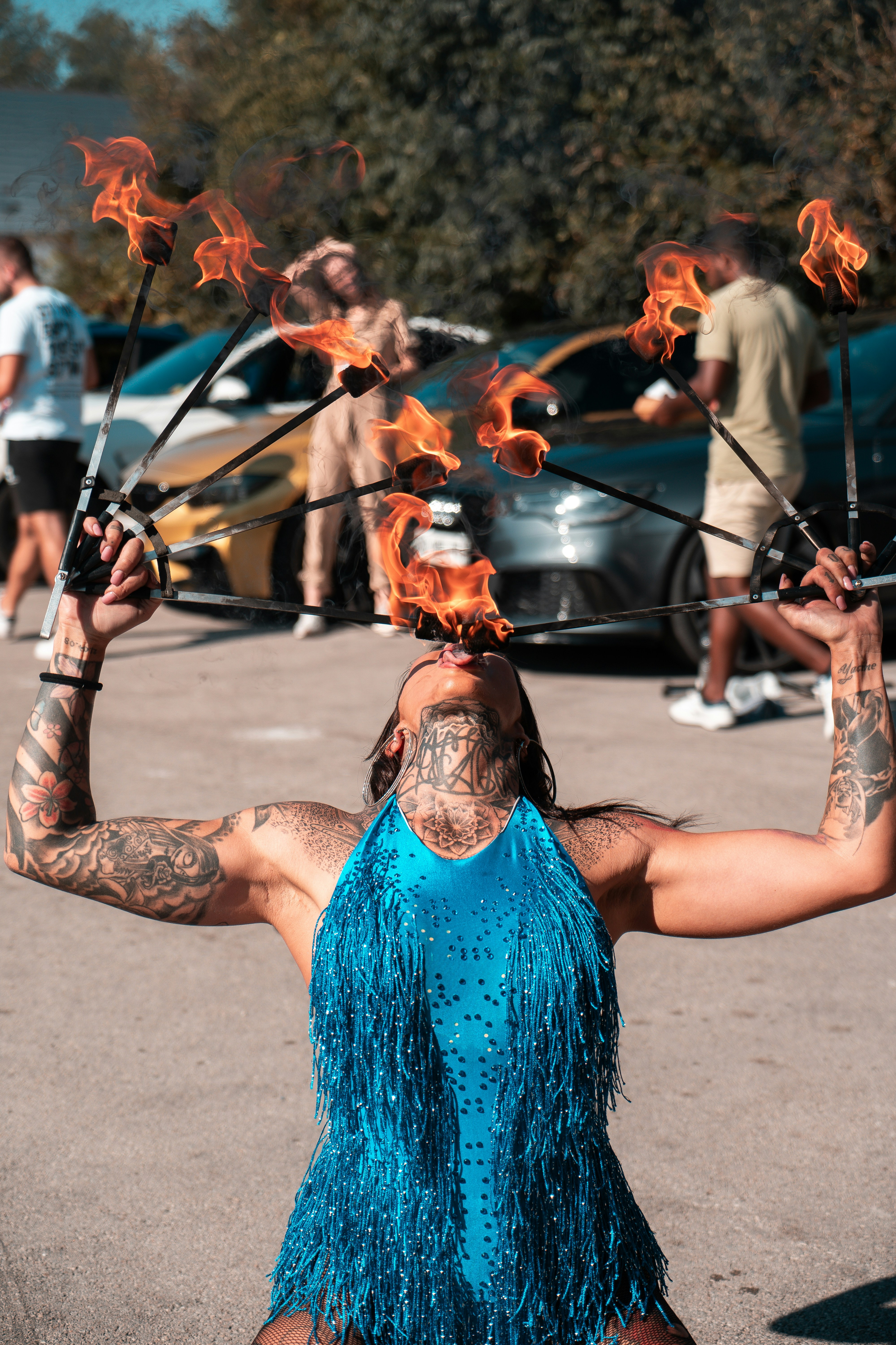 Fire-Breathing Performer in a Blue Fringe Dress at an Outdoor Gathering
