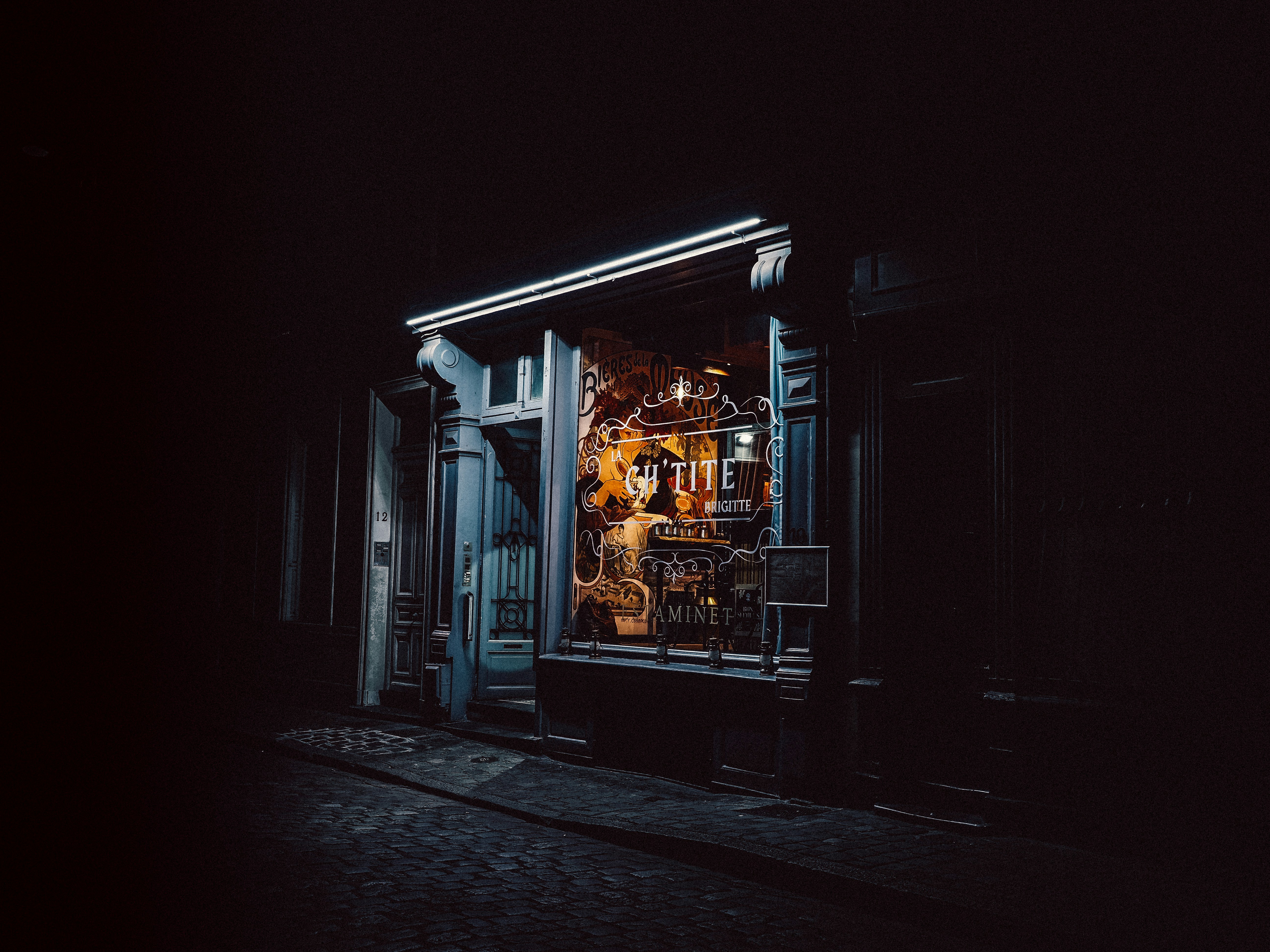 Dimly lit shop window displaying eclectic items on a dark street at night.